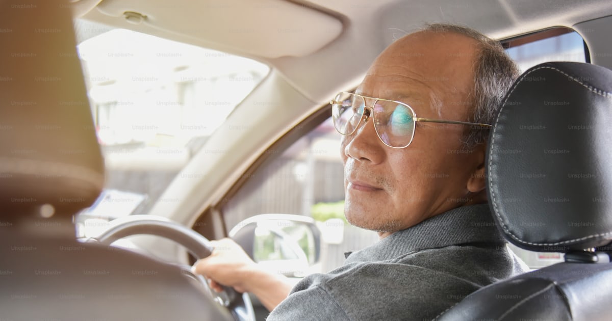車を運転する眼鏡をかけたリラックスしたアジアの年配の男性。成功と幸福のコンセプト。笑顔。退職の写真 Unsplashの運輸の画像