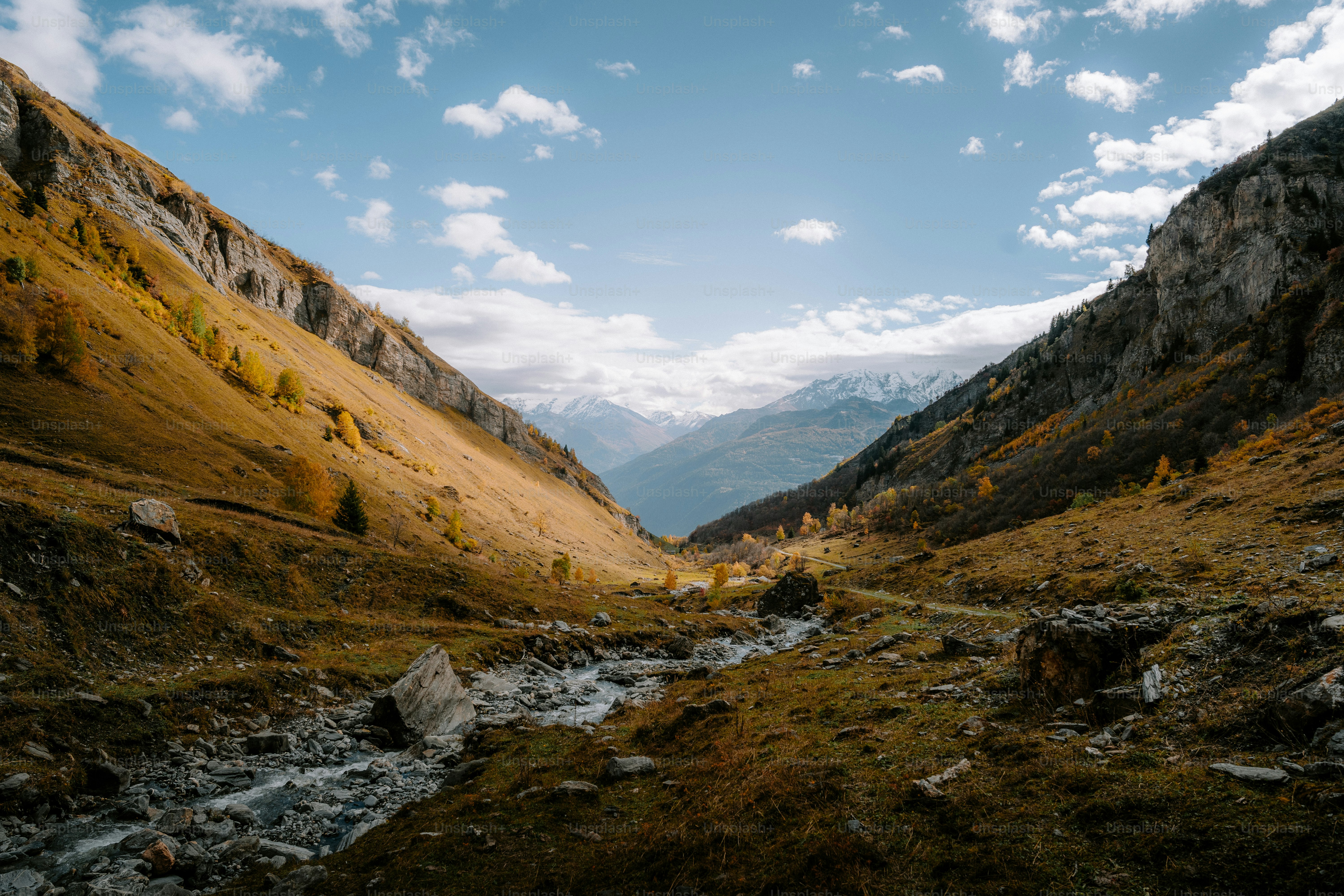 A stream running through a valley surrounded by mountains photo ...