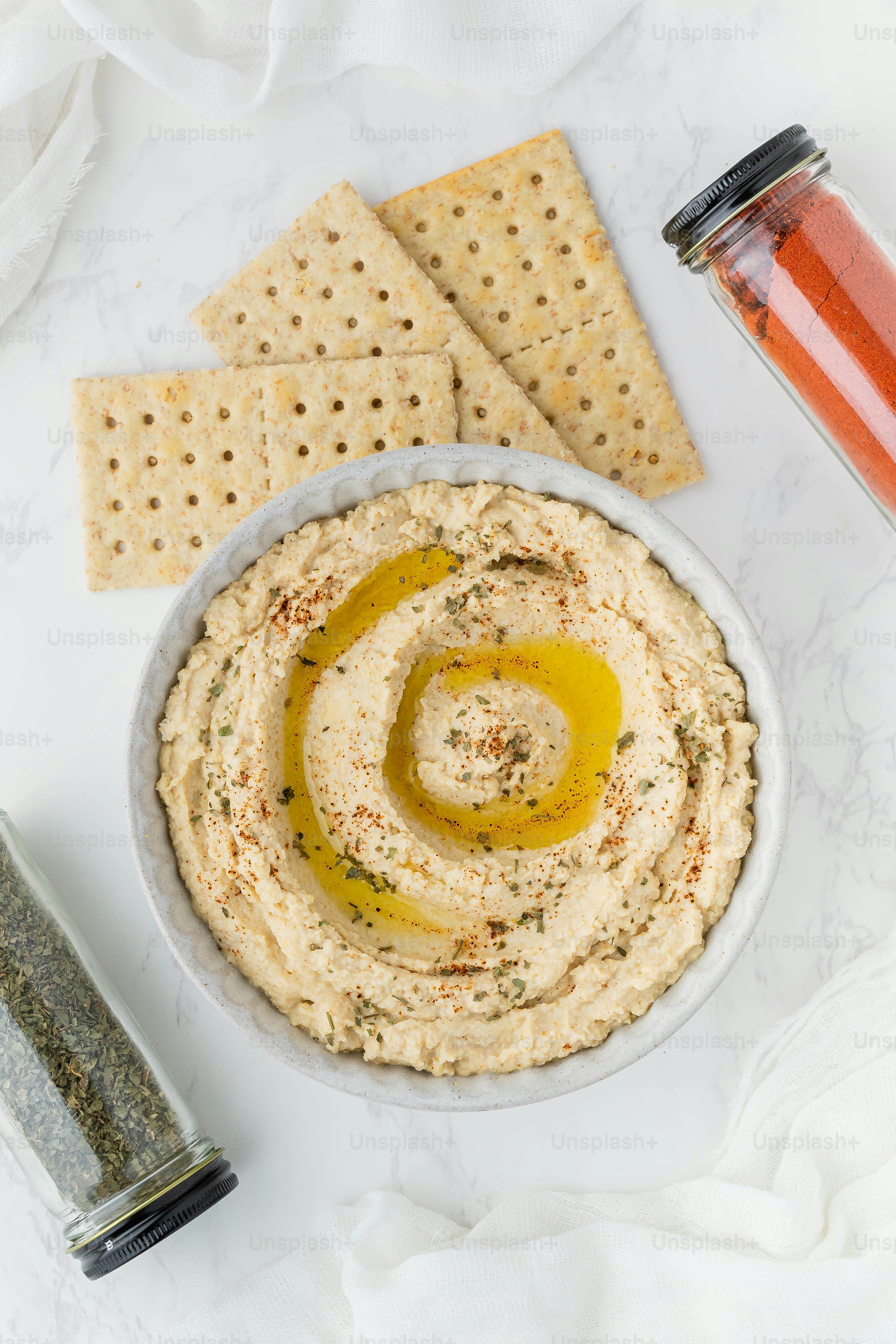 Un bol de houmous à côté de craquelins et un pot de moutarde photo ...