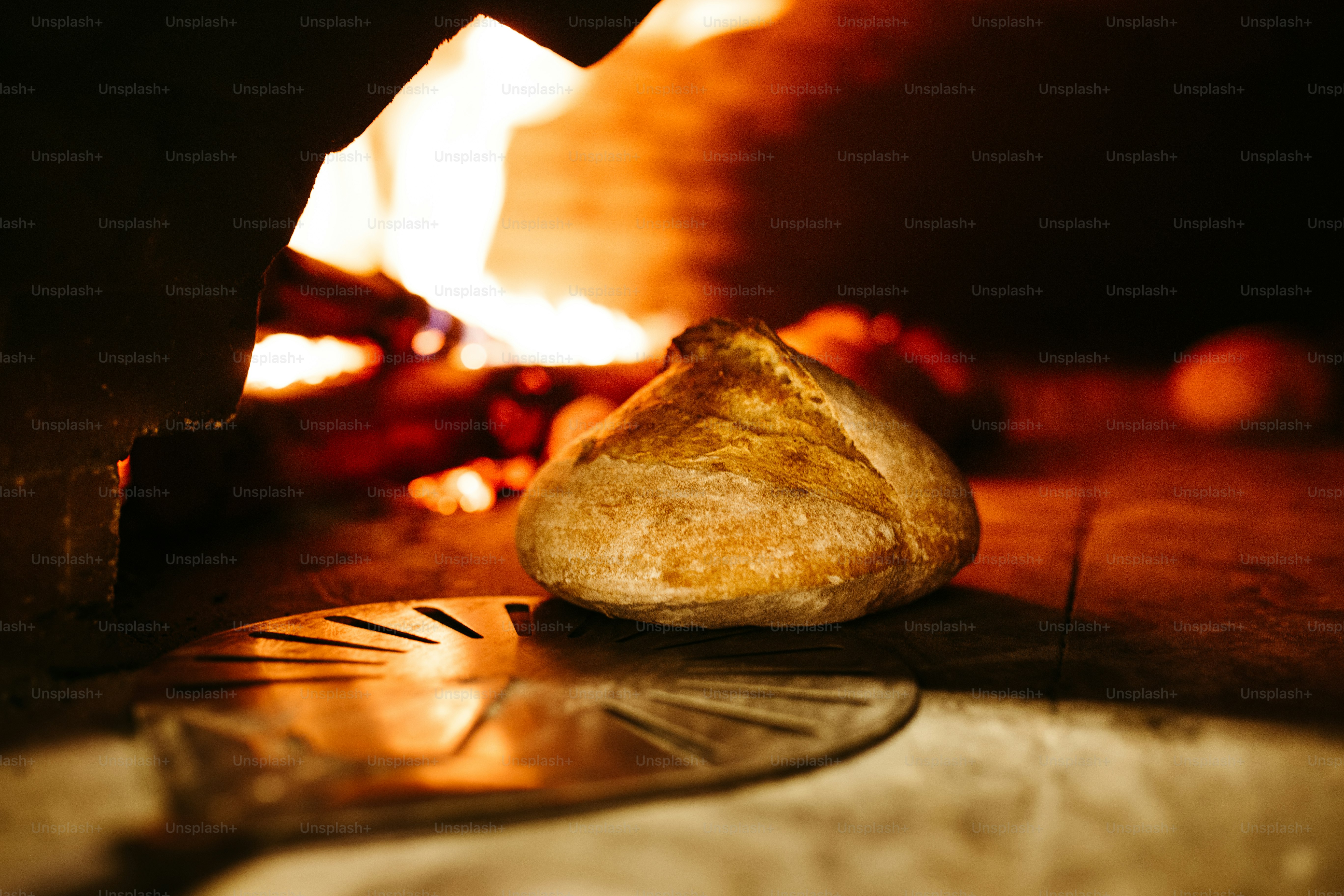 A loaf of bread sitting on a table in front of a fire photo – Bread ...