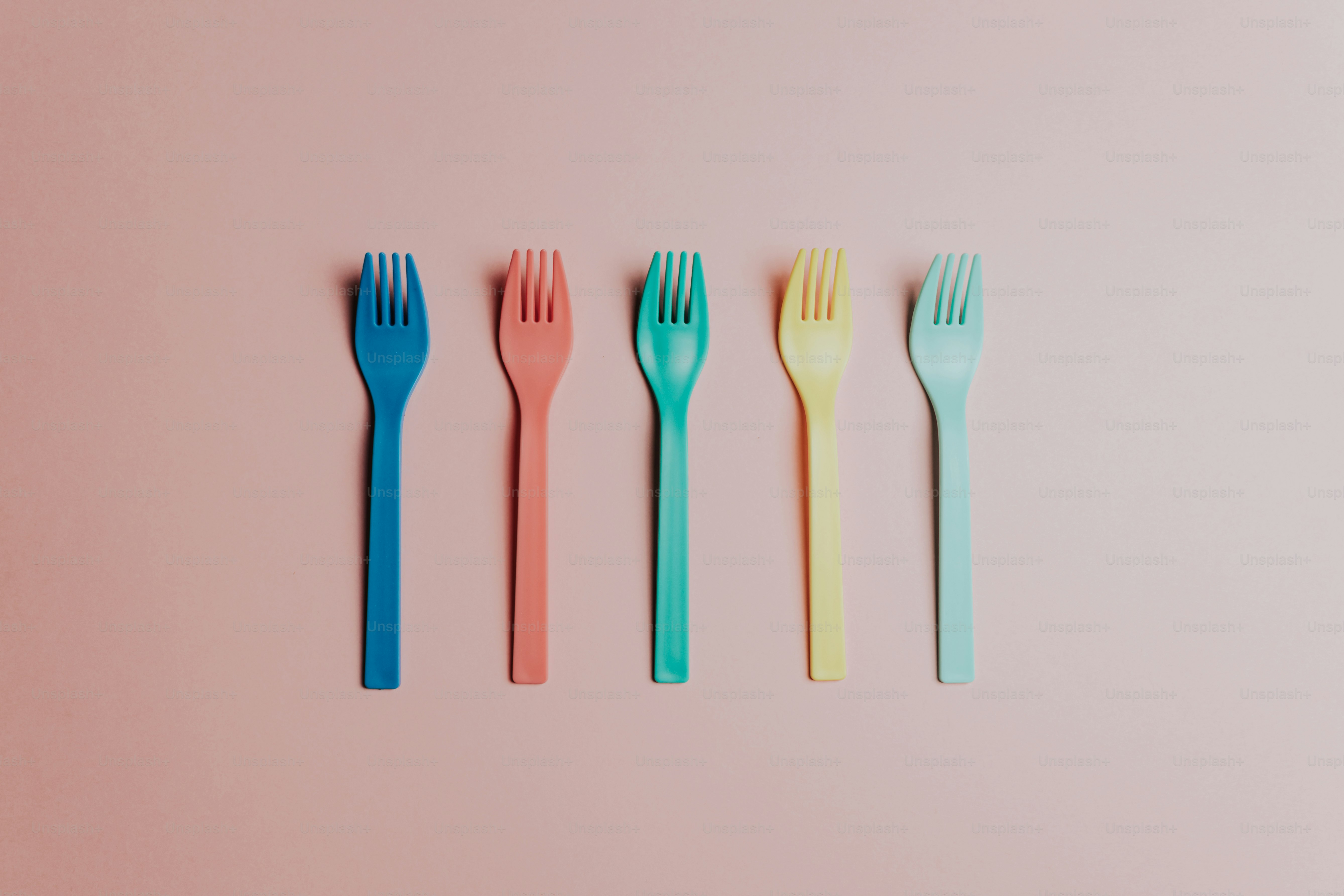 Four forks lined up in a row on a pink surface photo – Cutlery Image on ...