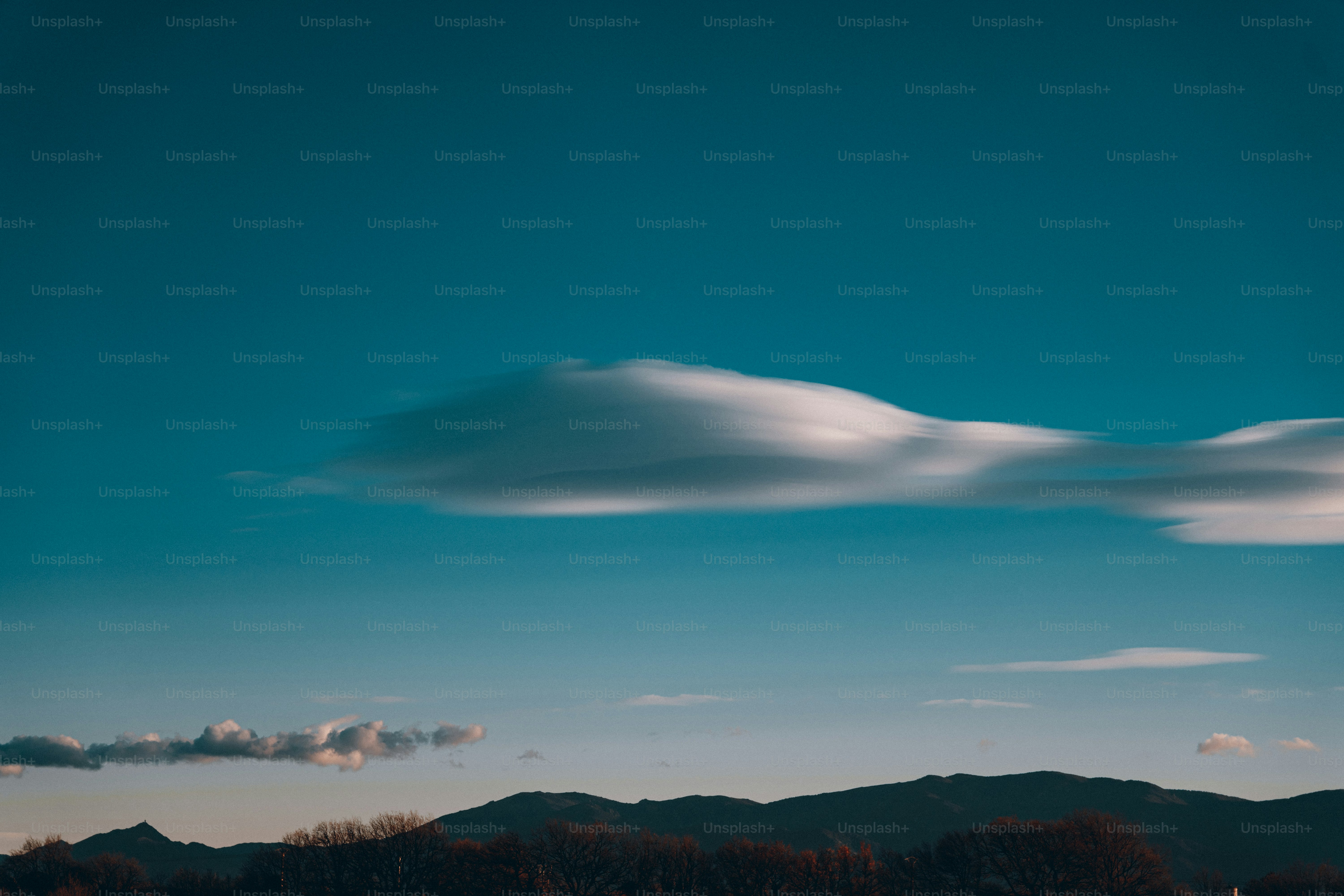 Un gros nuage est dans le ciel au-dessus d’une montagne photo – Image ...