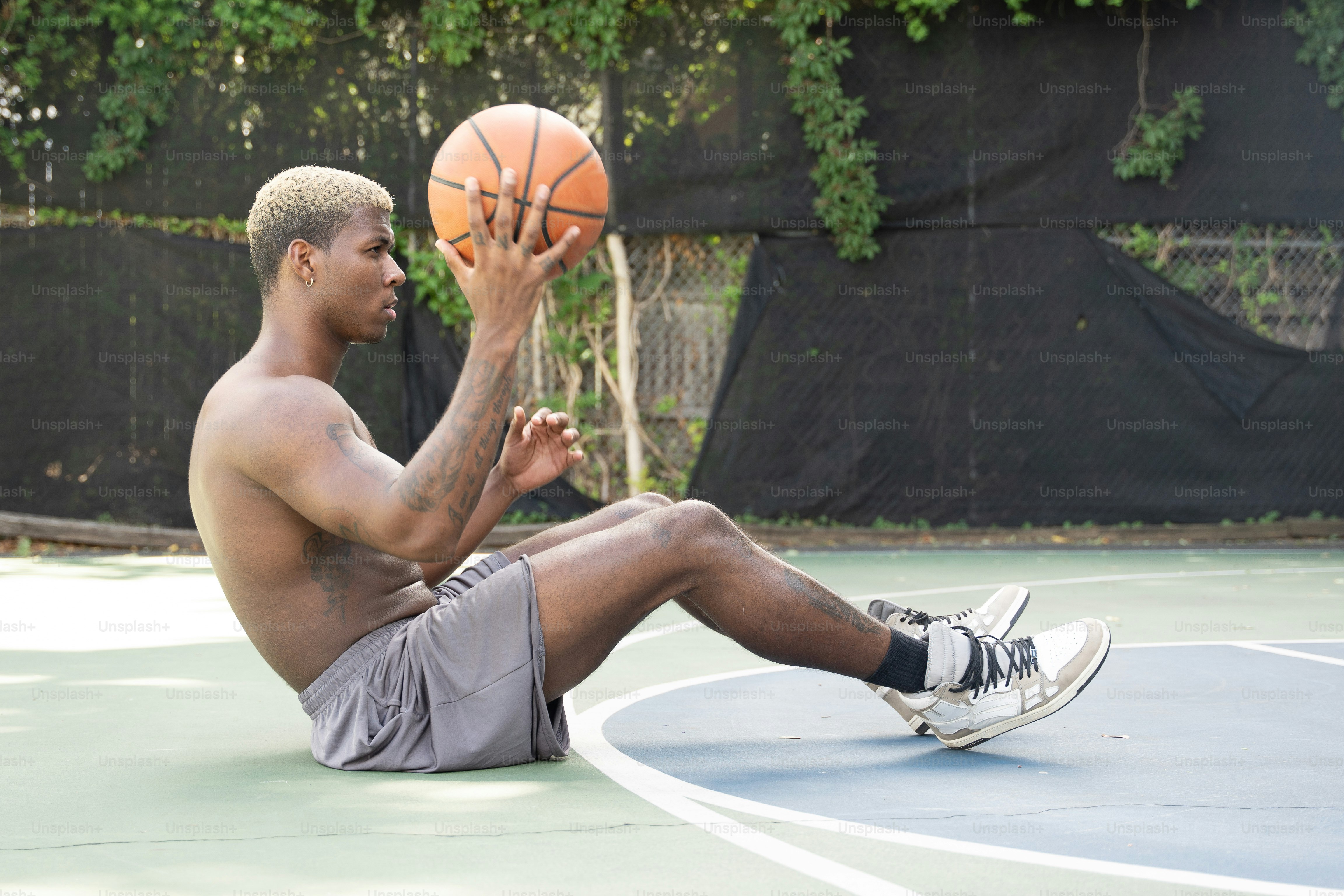 A man sitting on a basketball court holding a basketball photo – No ...