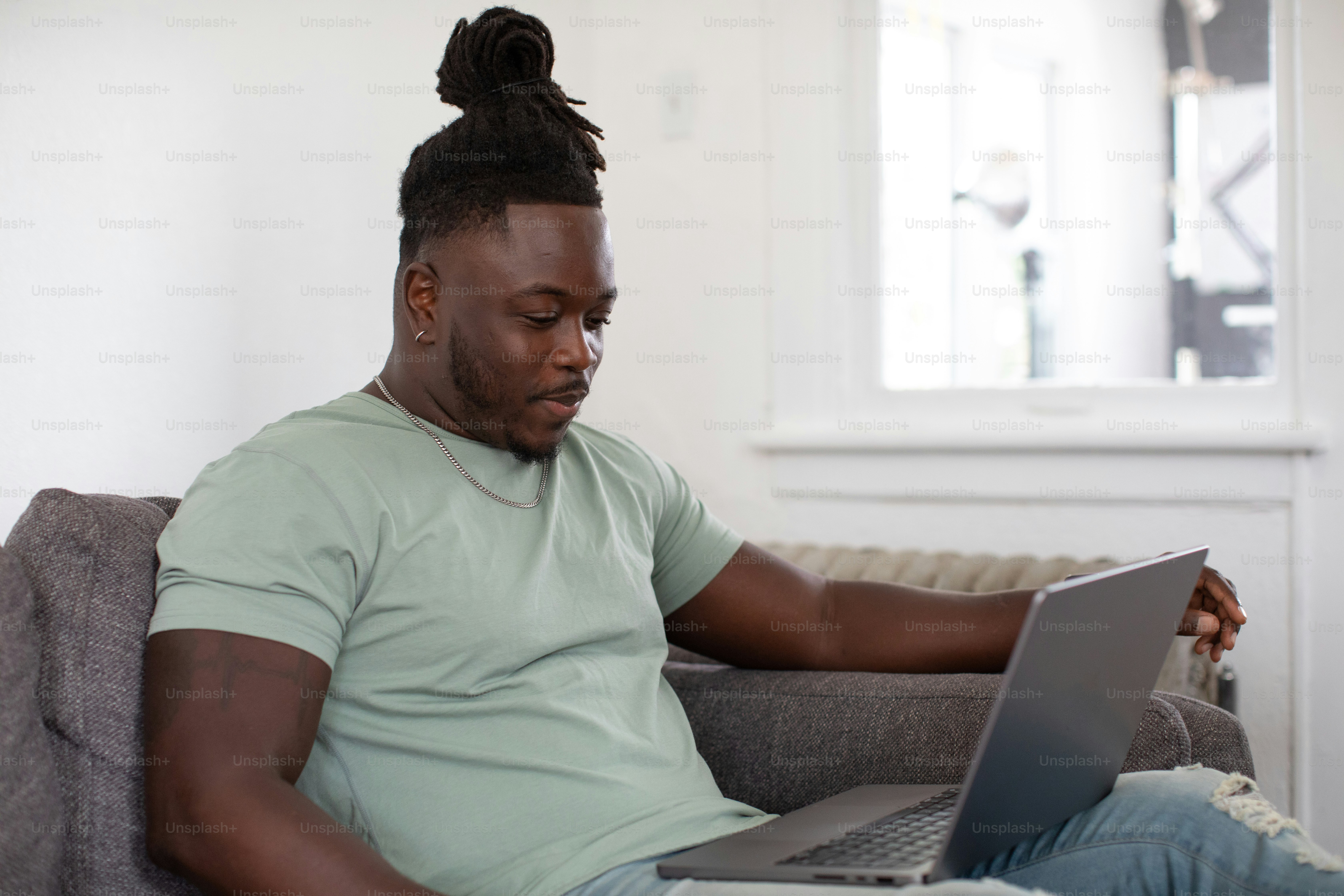 Un homme assis sur un canapé utilisant un ordinateur portable photo ...