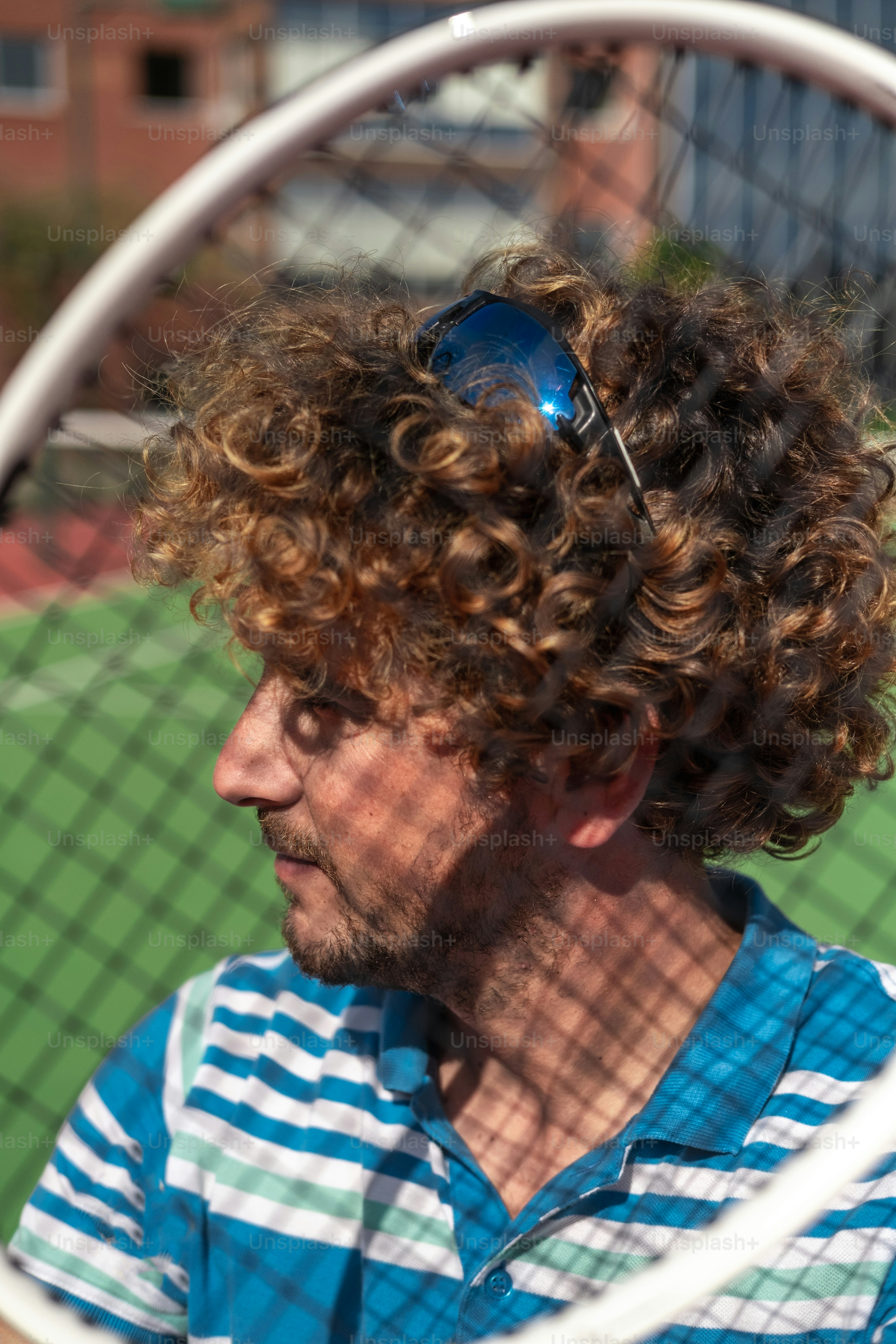 A man with curly hair holding a tennis racket photo – Tennis Image on ...