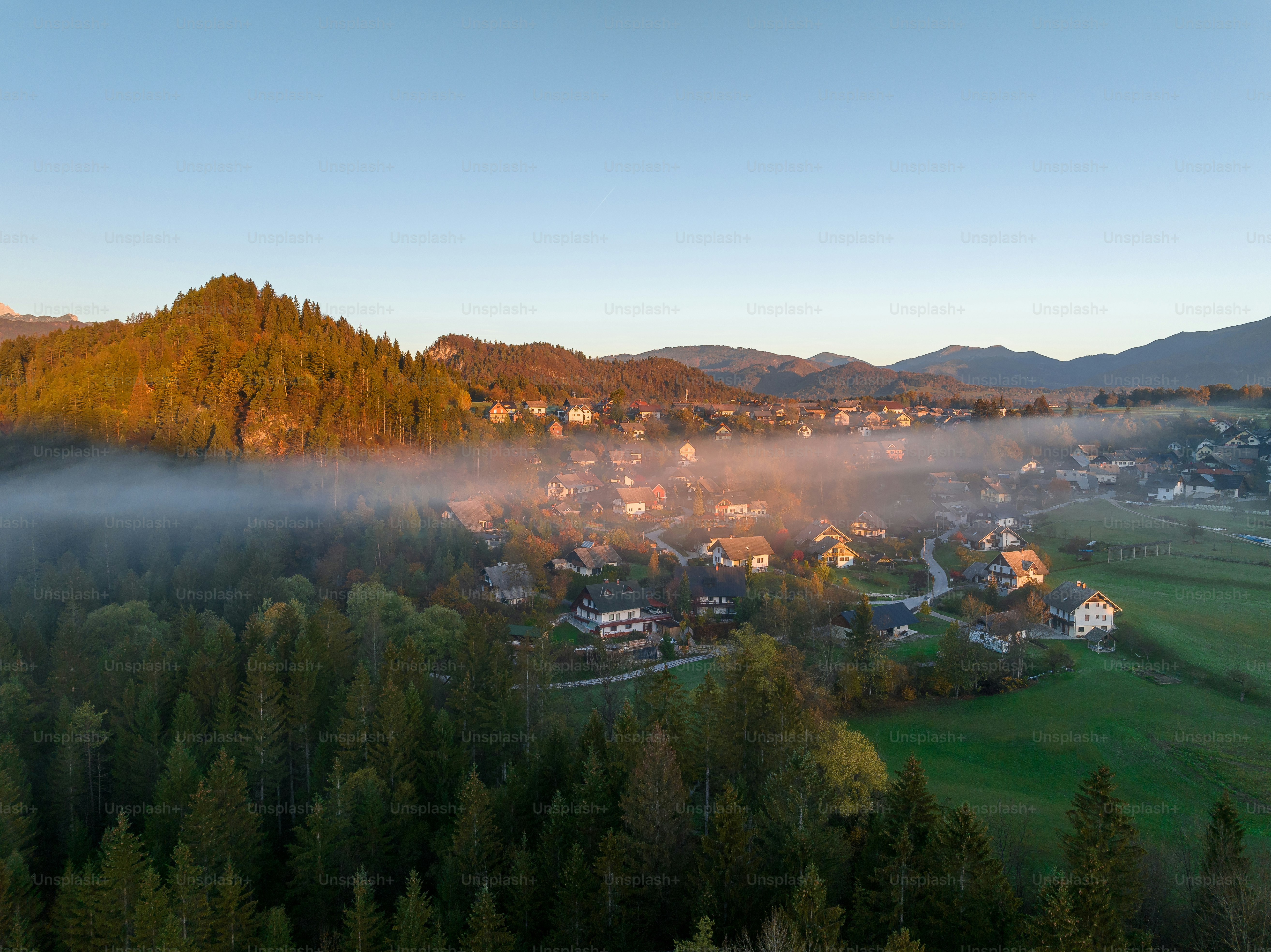 A small town surrounded by trees in the mountains photo – Mist Image on ...