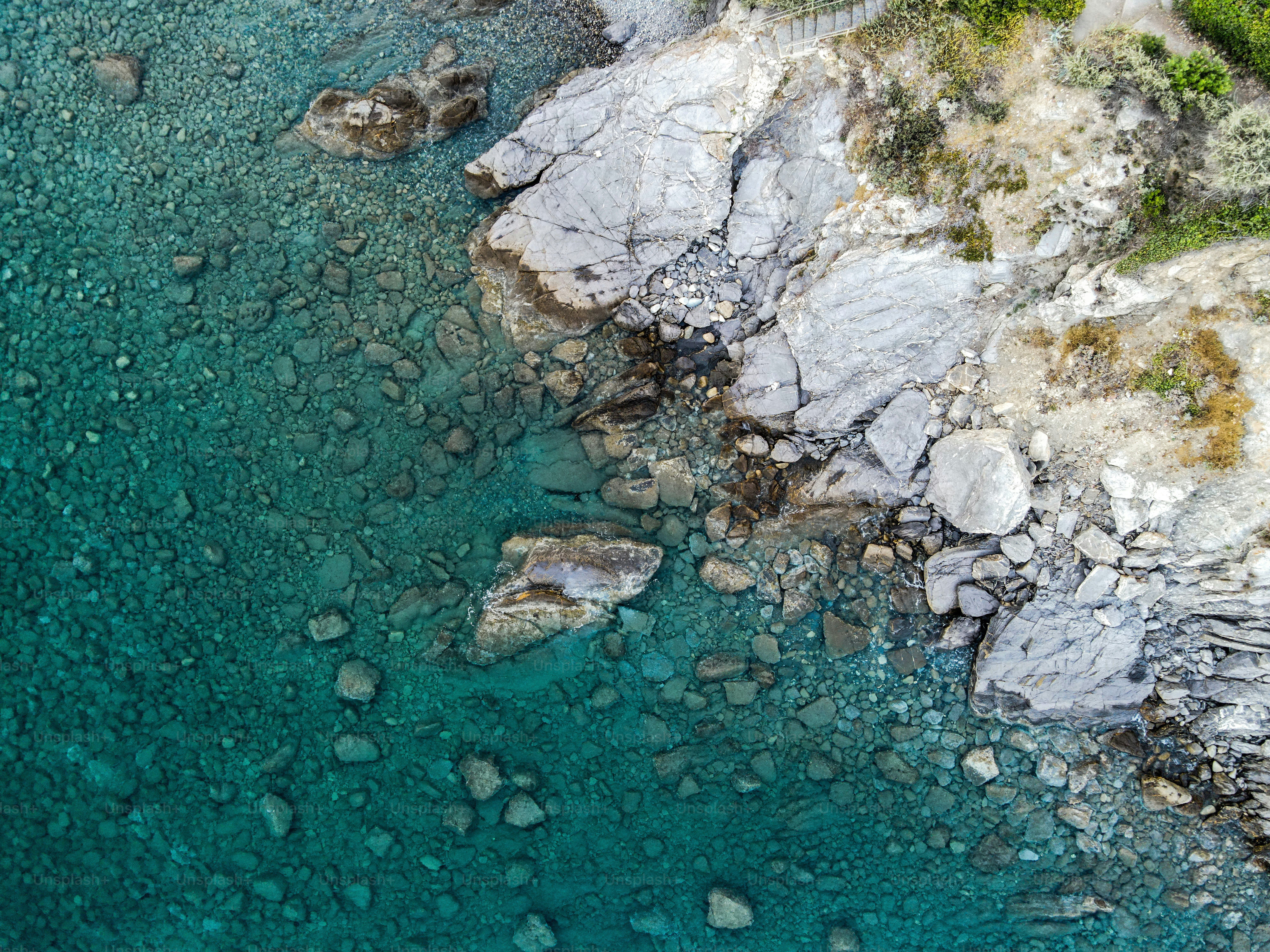 An aerial view of a body of water surrounded by rocks photo – Sea Image ...
