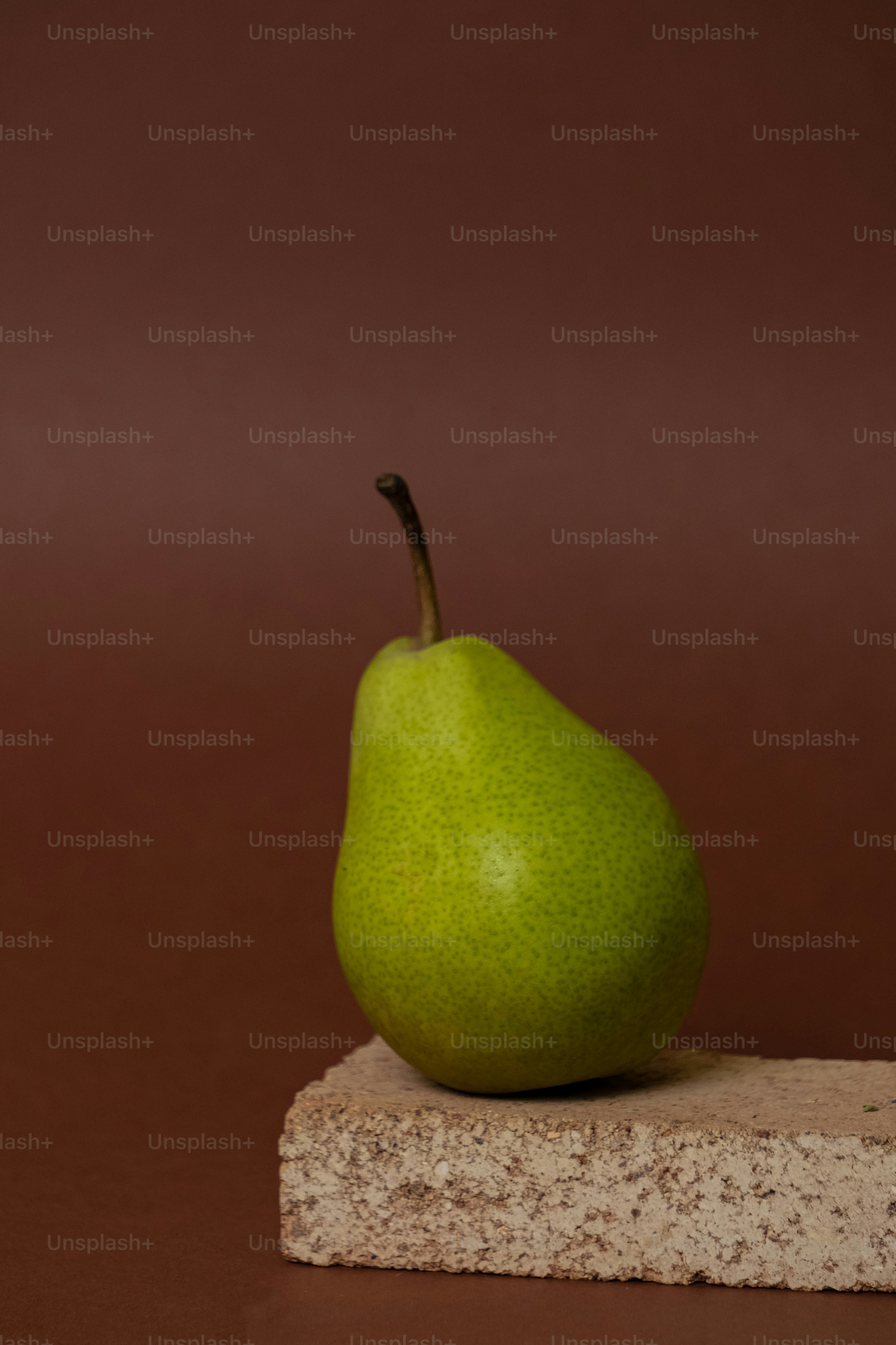 A green pear sitting on top of a stone block photo – Pear Image on Unsplash