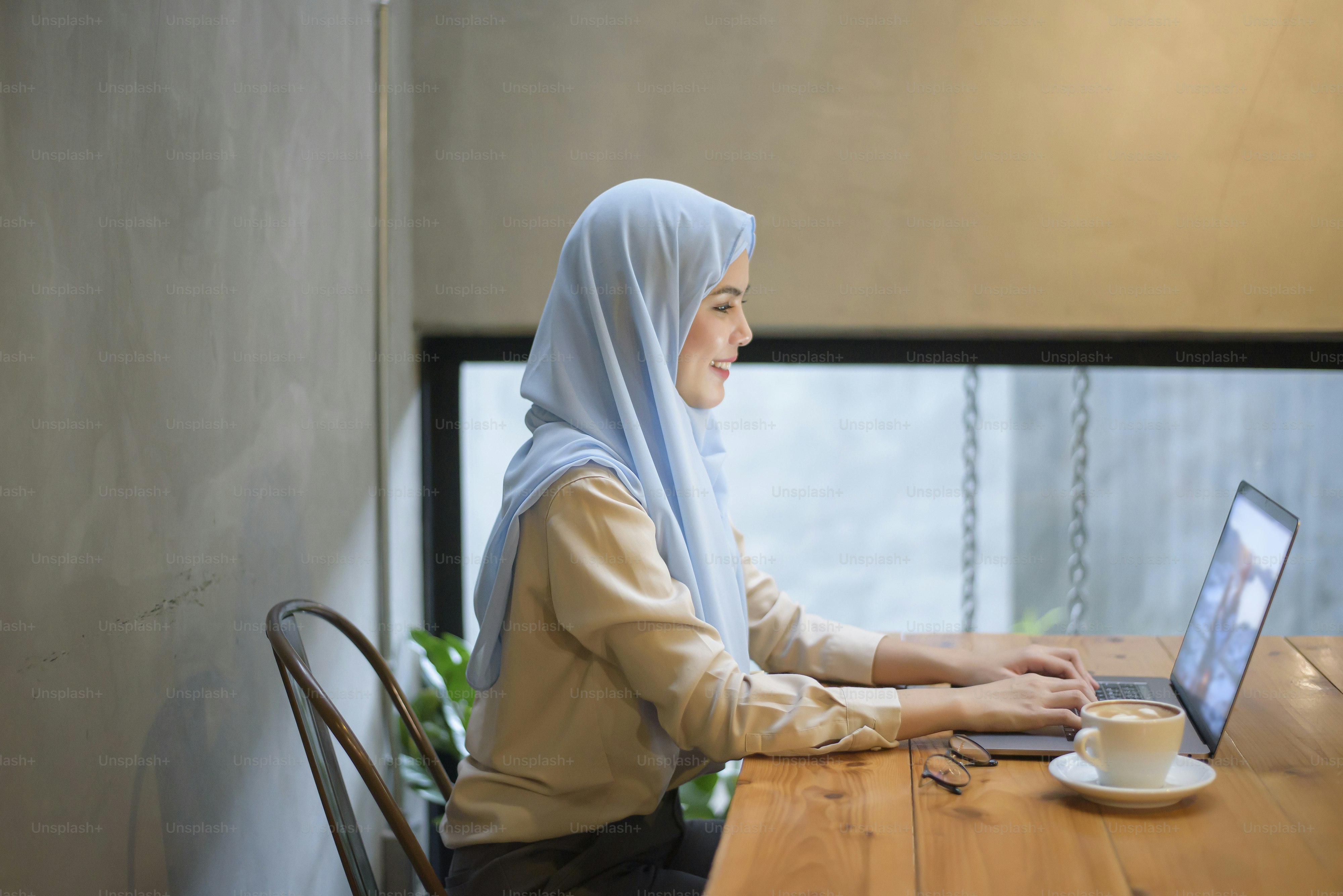 Muslim woman with hijab is working with laptop computer in coffee shop ...