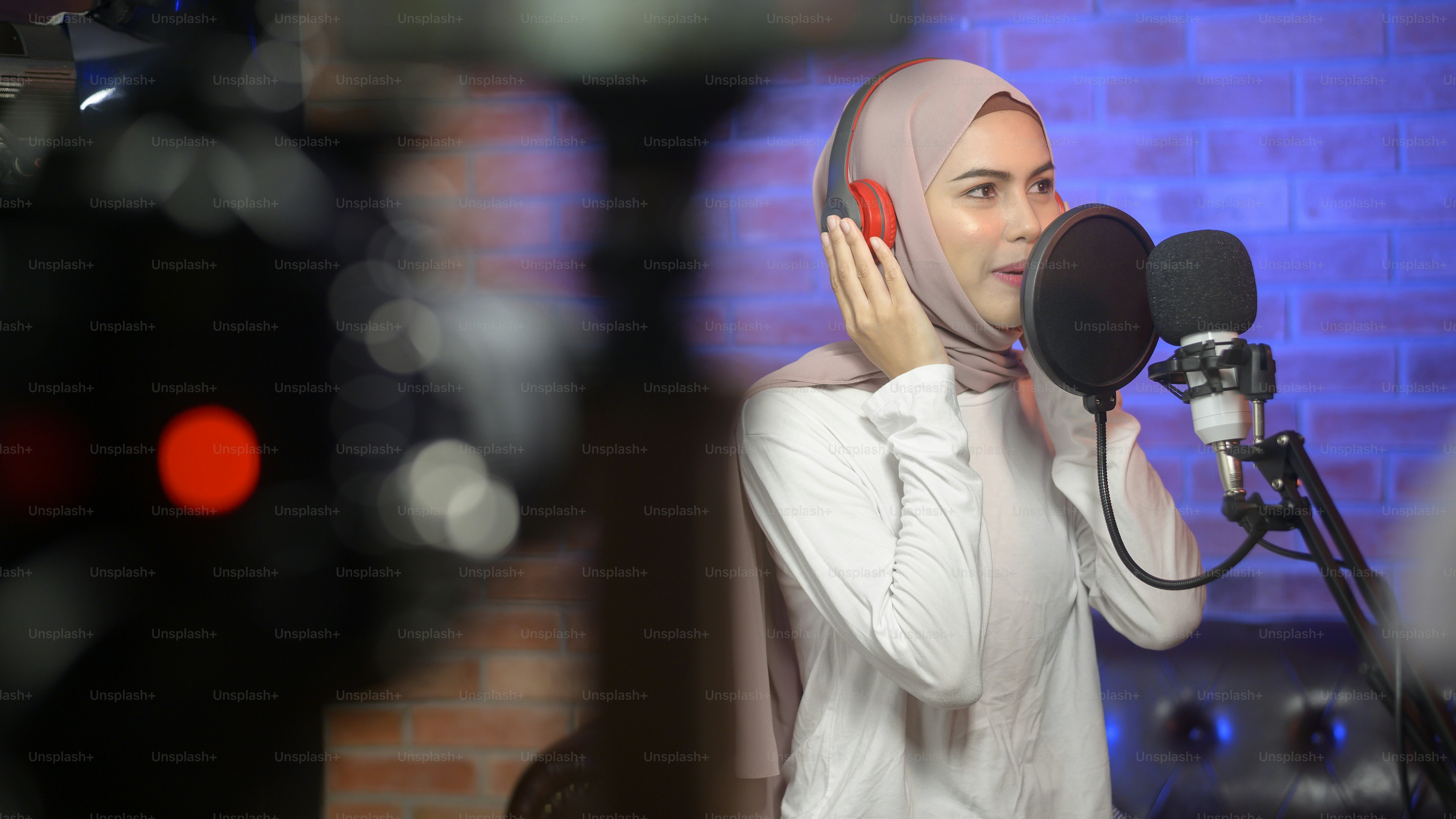 A young smiling muslim female singer wearing headphones with a ...