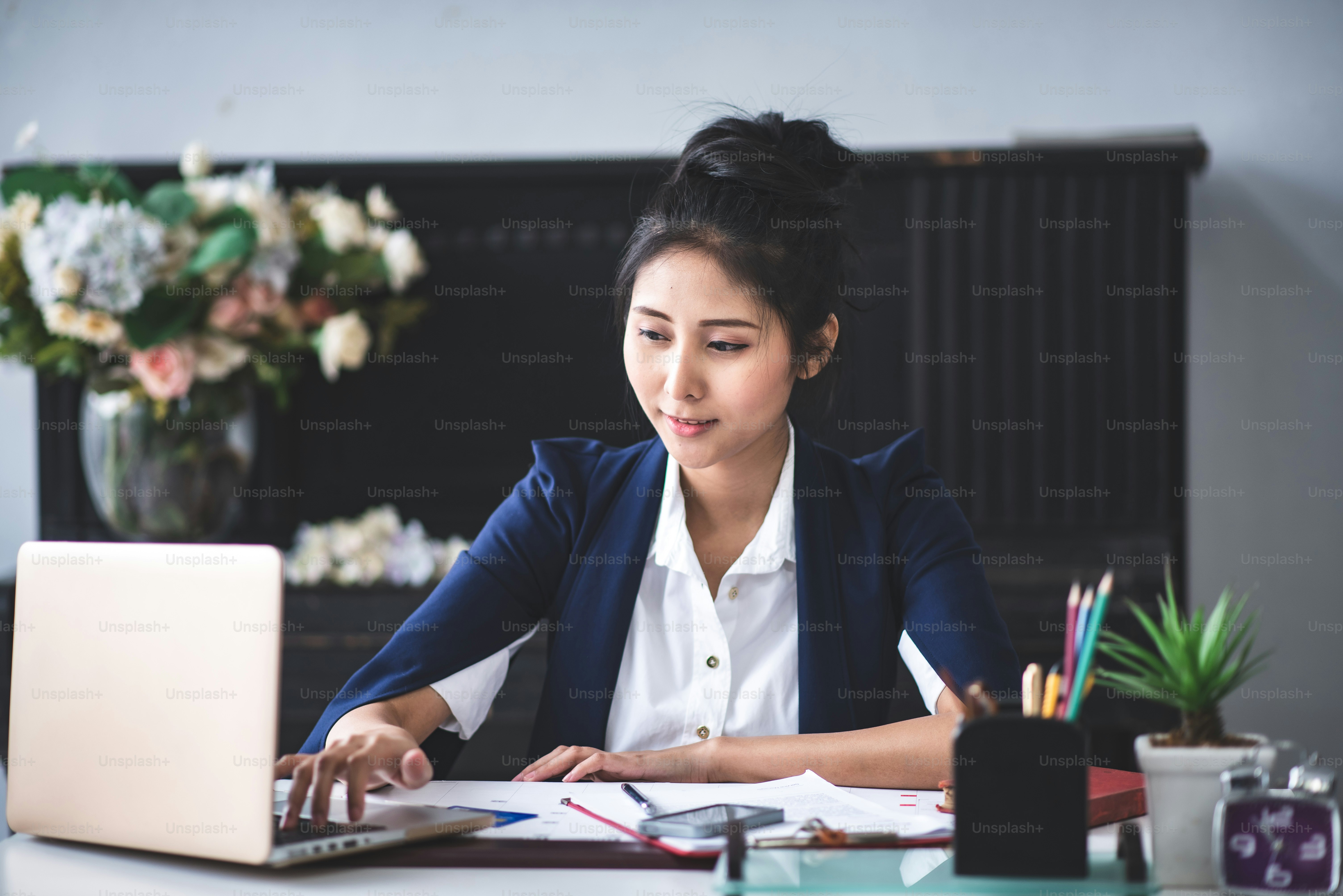 Portrait of smiling pretty young business woman sitting on workplace ...
