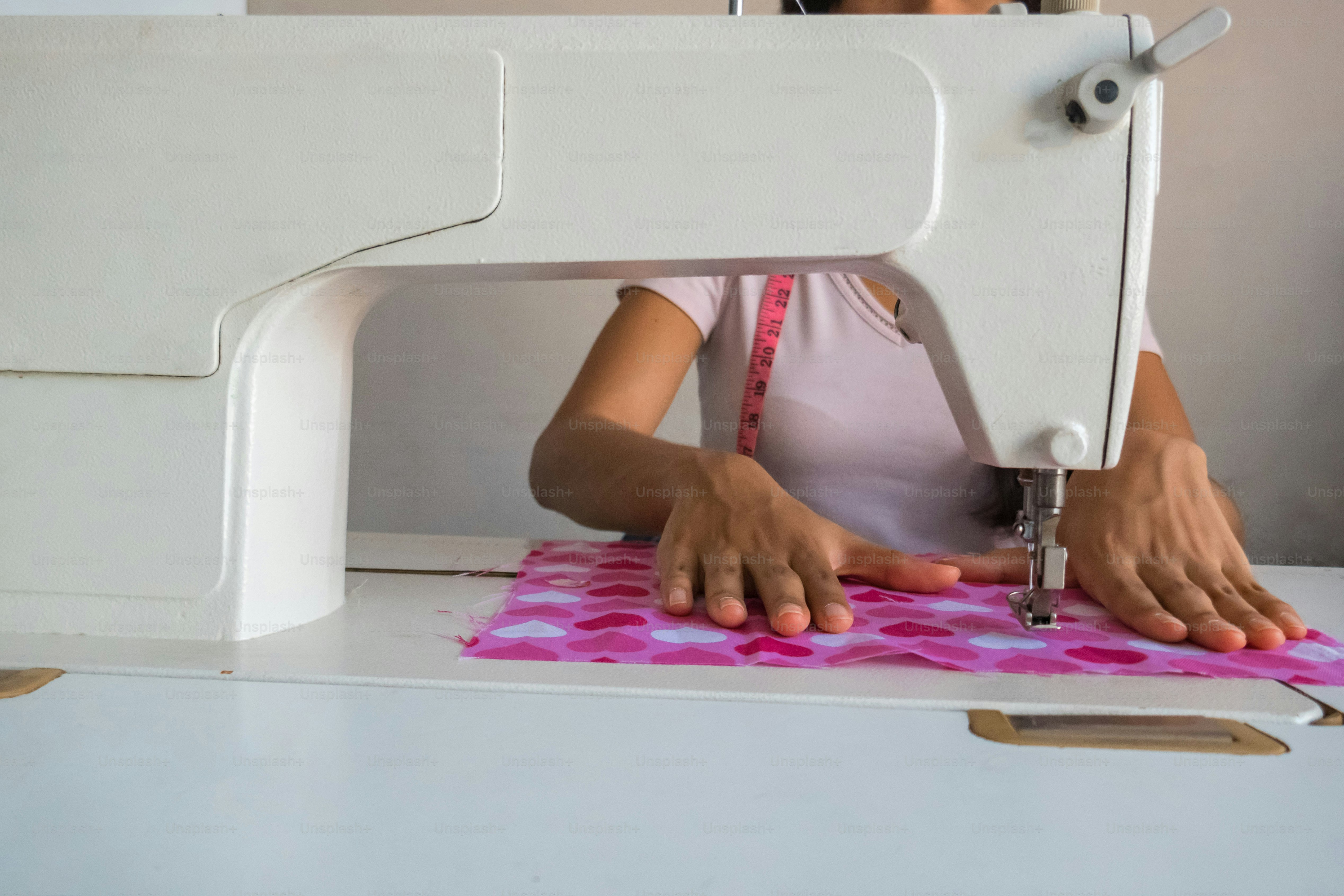 A young woman who uses a sewing machine in the tailor's shop. photo ...