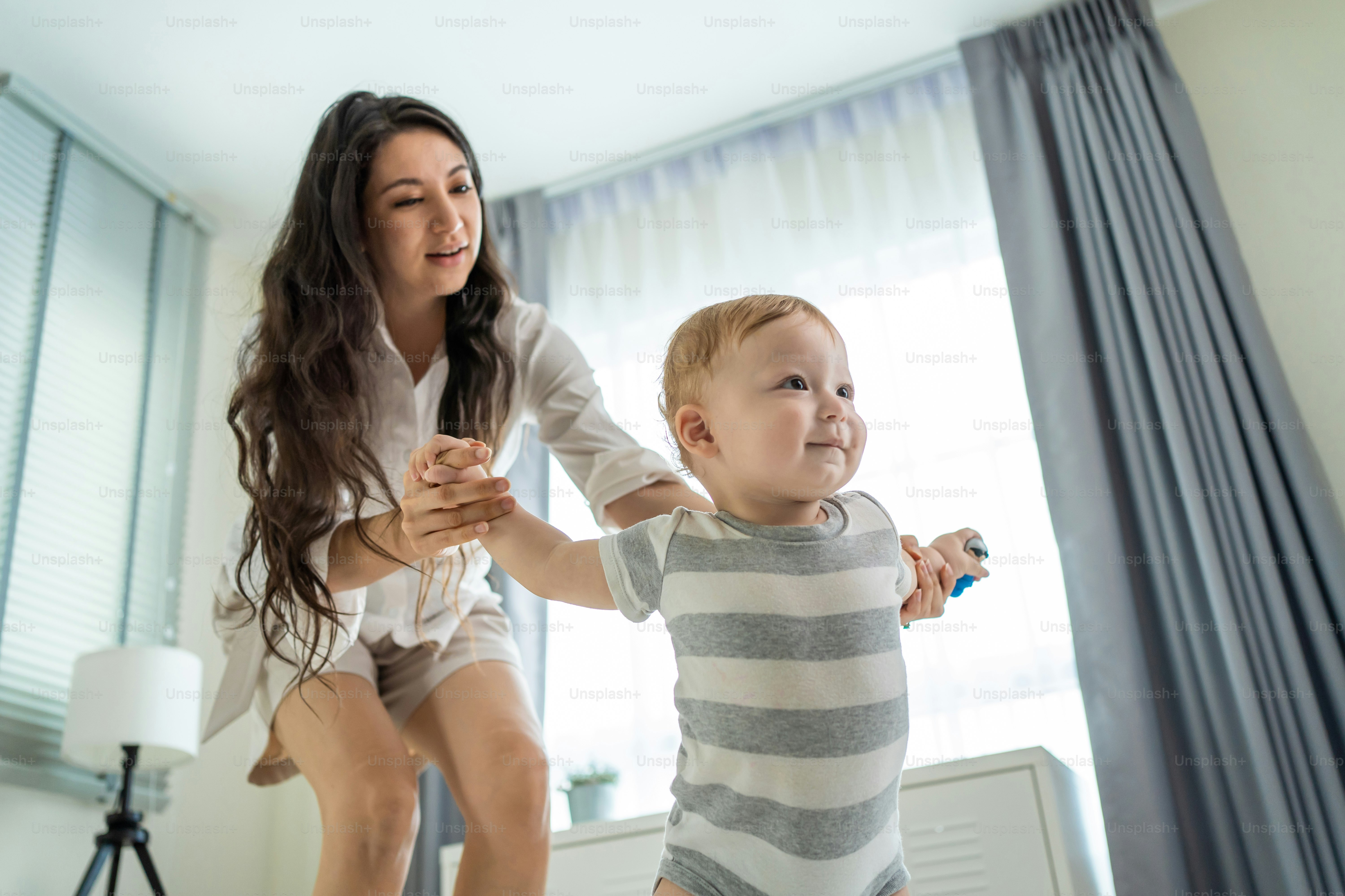 Caucasian young cute baby boy child learn to walk with parent in house ...