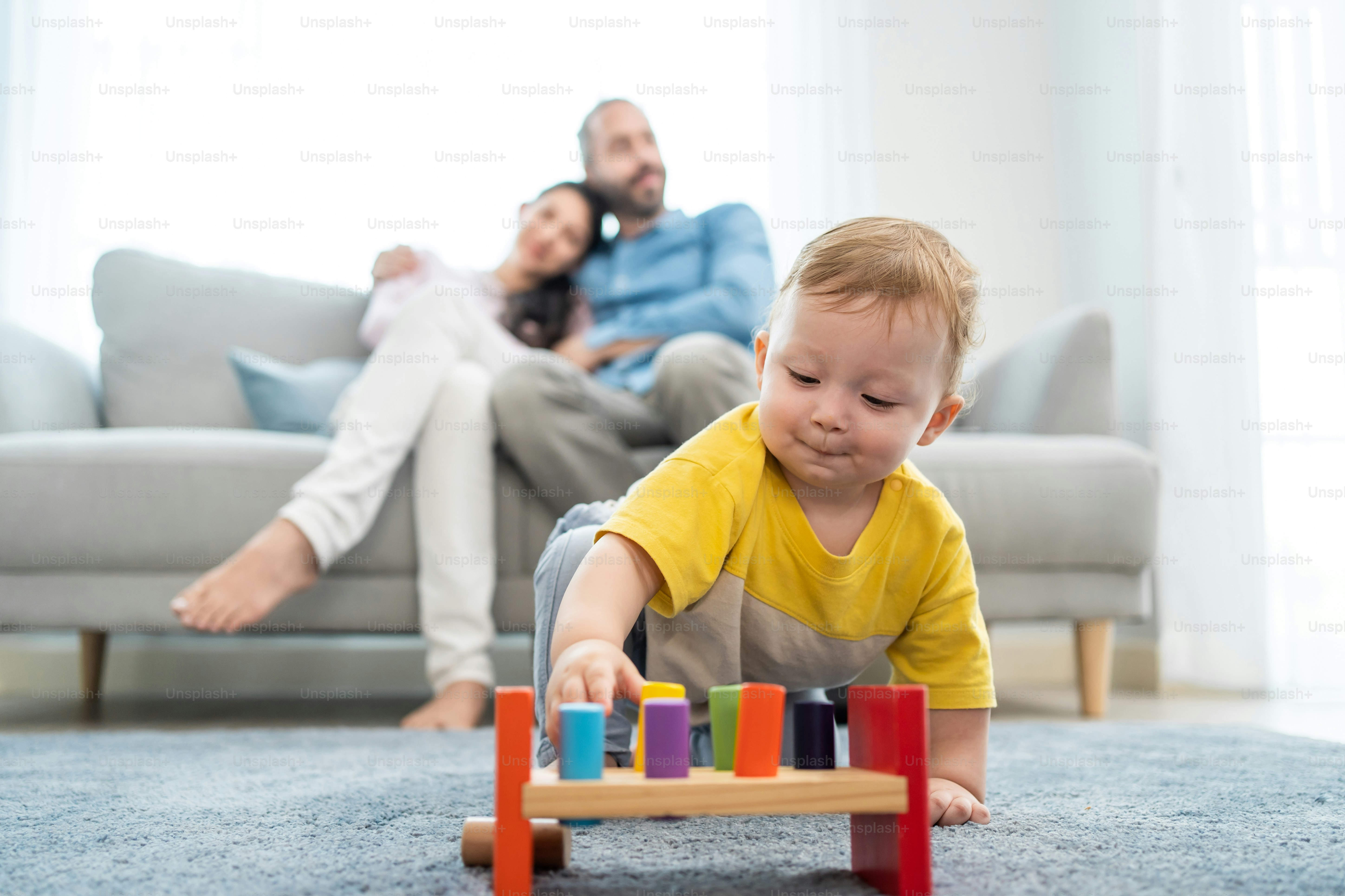 Caucasian loving parent looking at baby toddler playing in living room ...