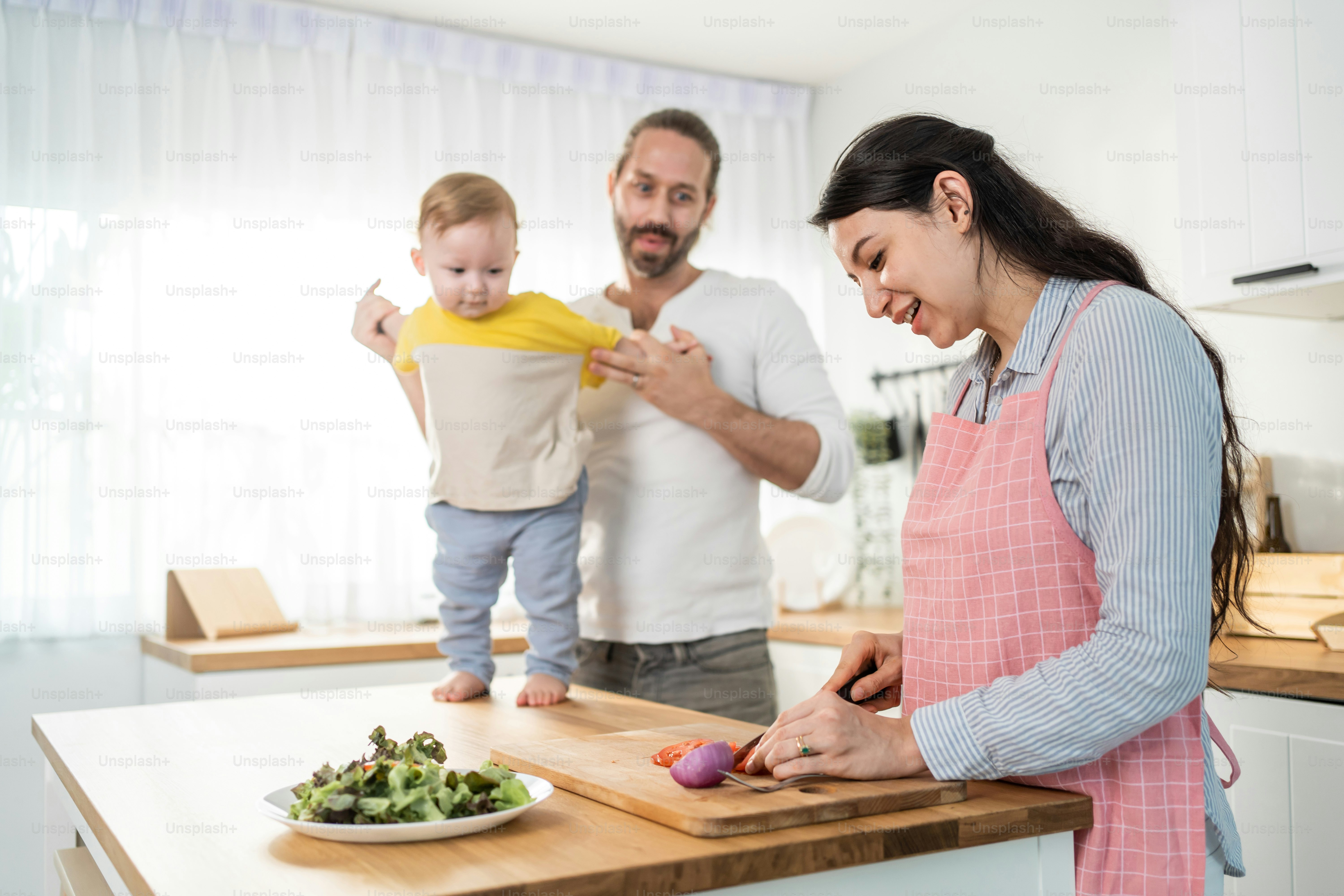 Caucasian beautiful parents cook food with baby boy toddler in kitchen ...