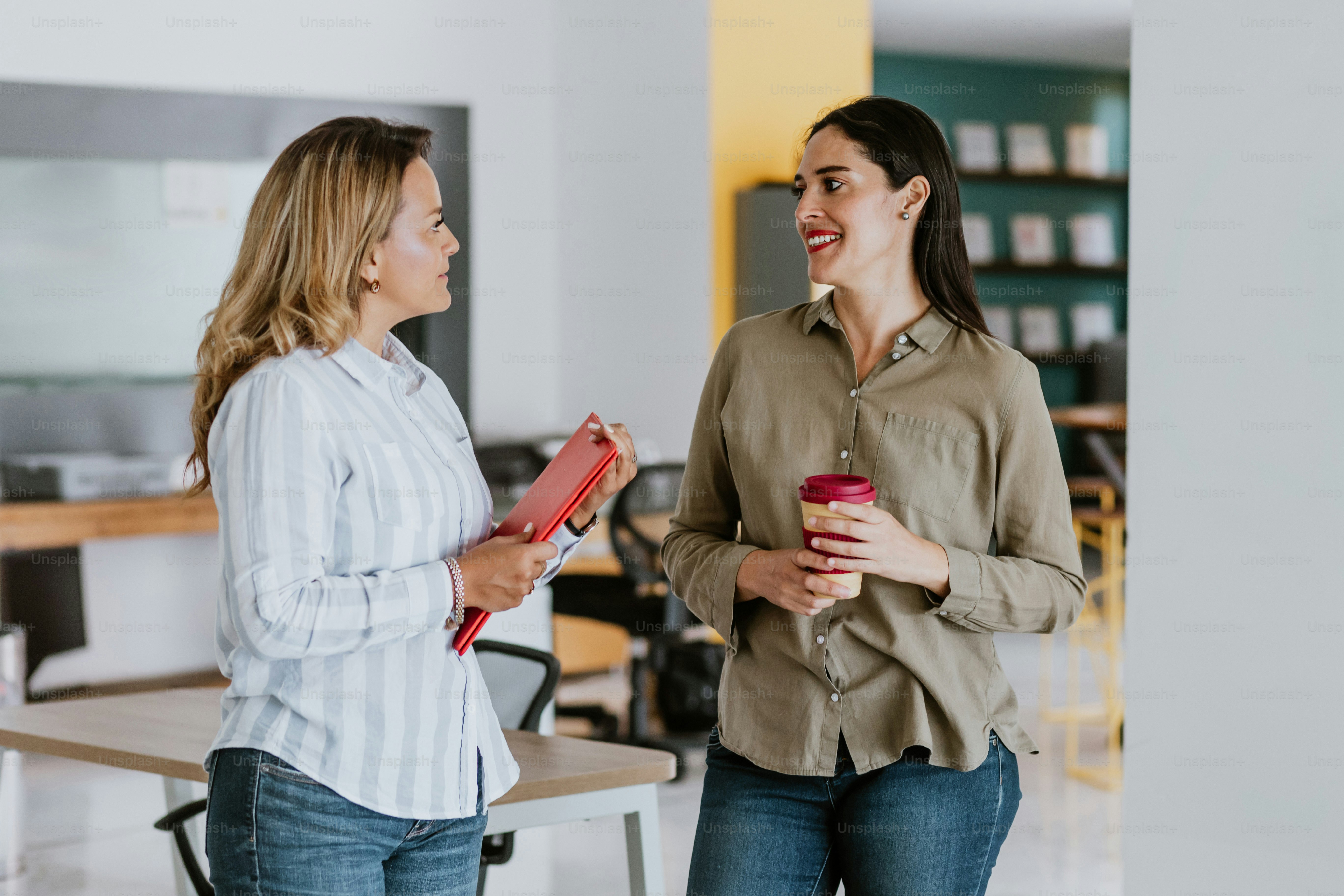 Two latin business woman middle age, talking and advising each other at ...