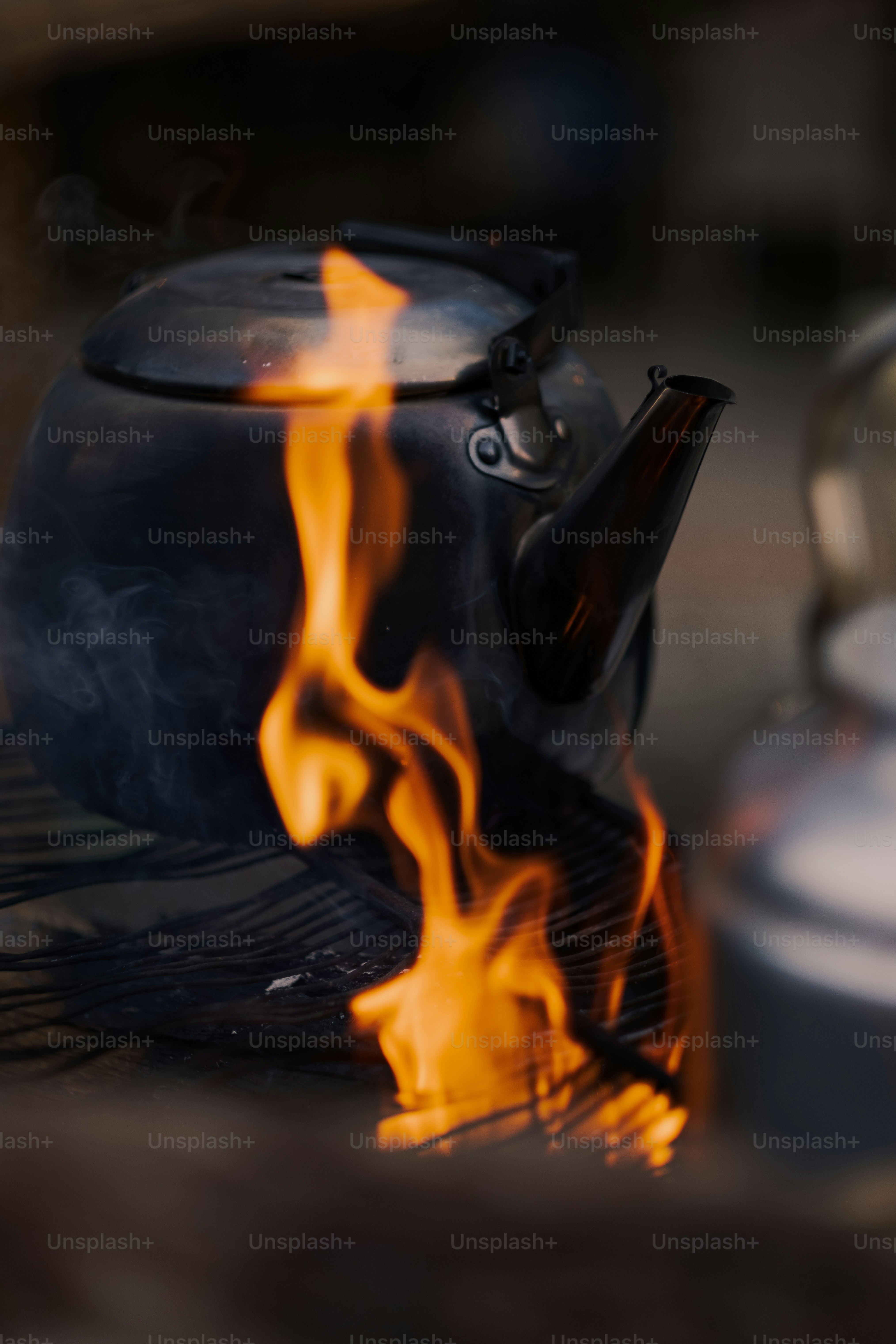 A tea pot on a grill with flames coming out of it photo – Tea kettle ...