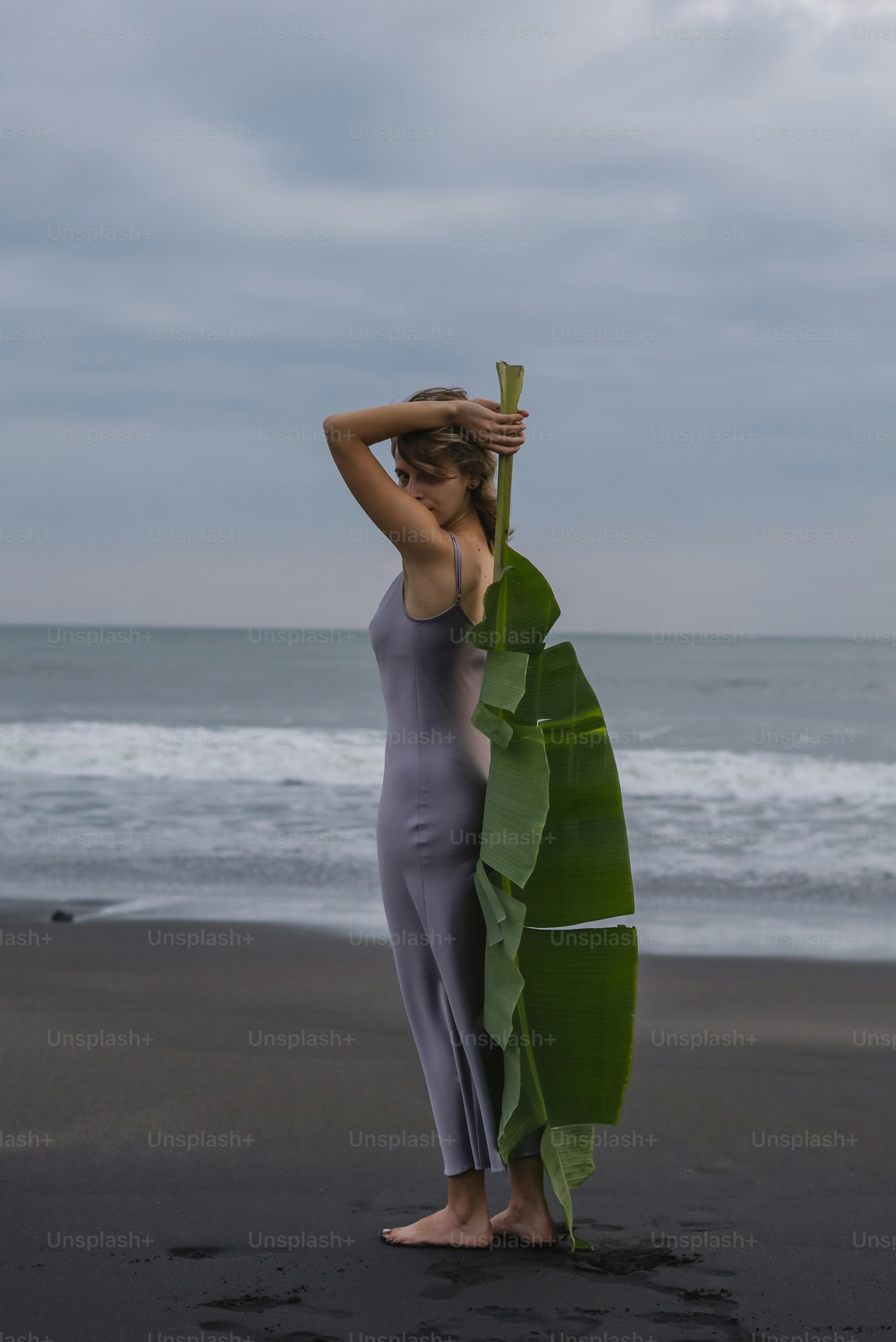 Foto Una mujer parada en una playa sosteniendo un plátano – Bali Imagen en Unsplash