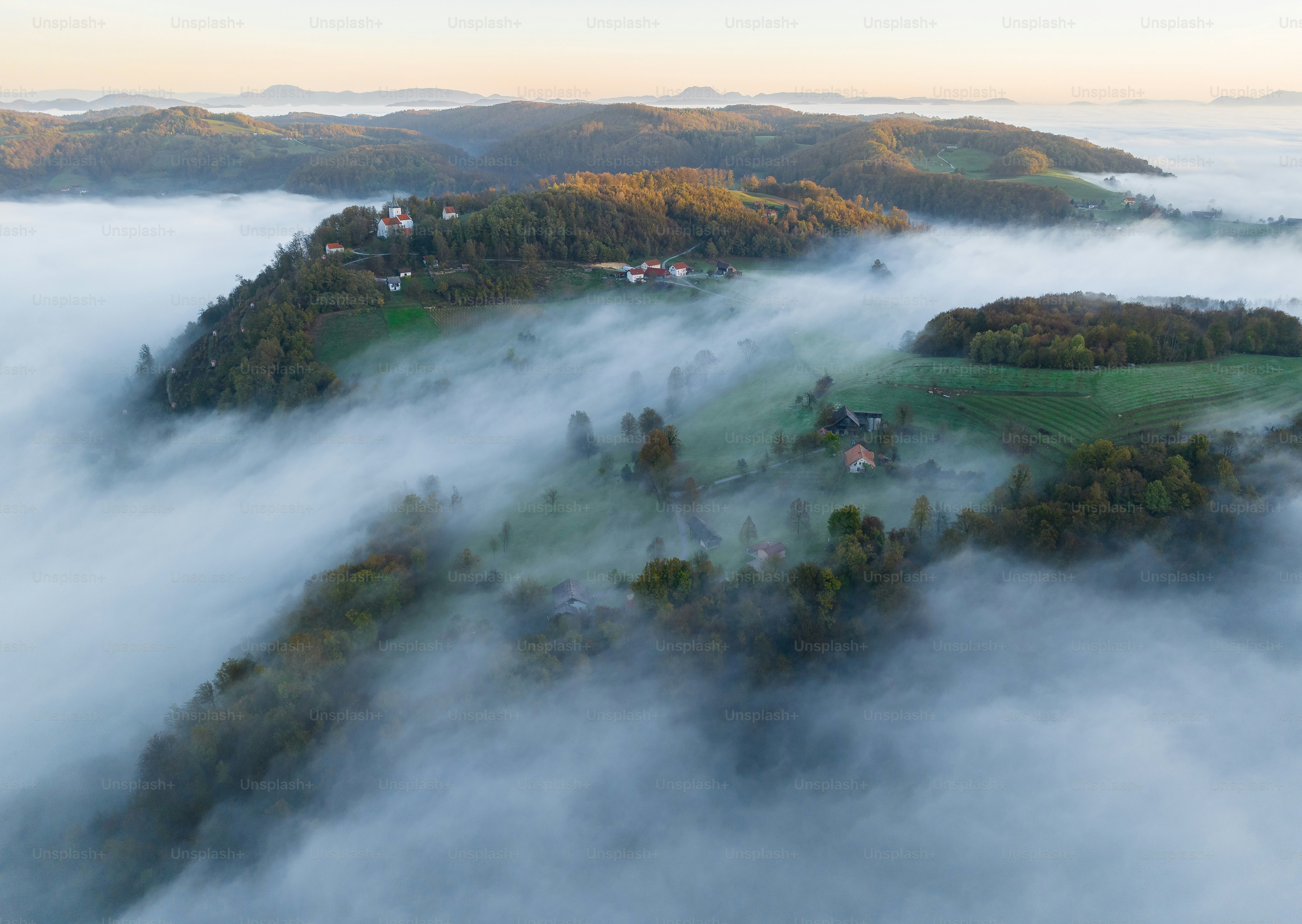 An aerial view of a small village surrounded by fog photo – Foggy ...