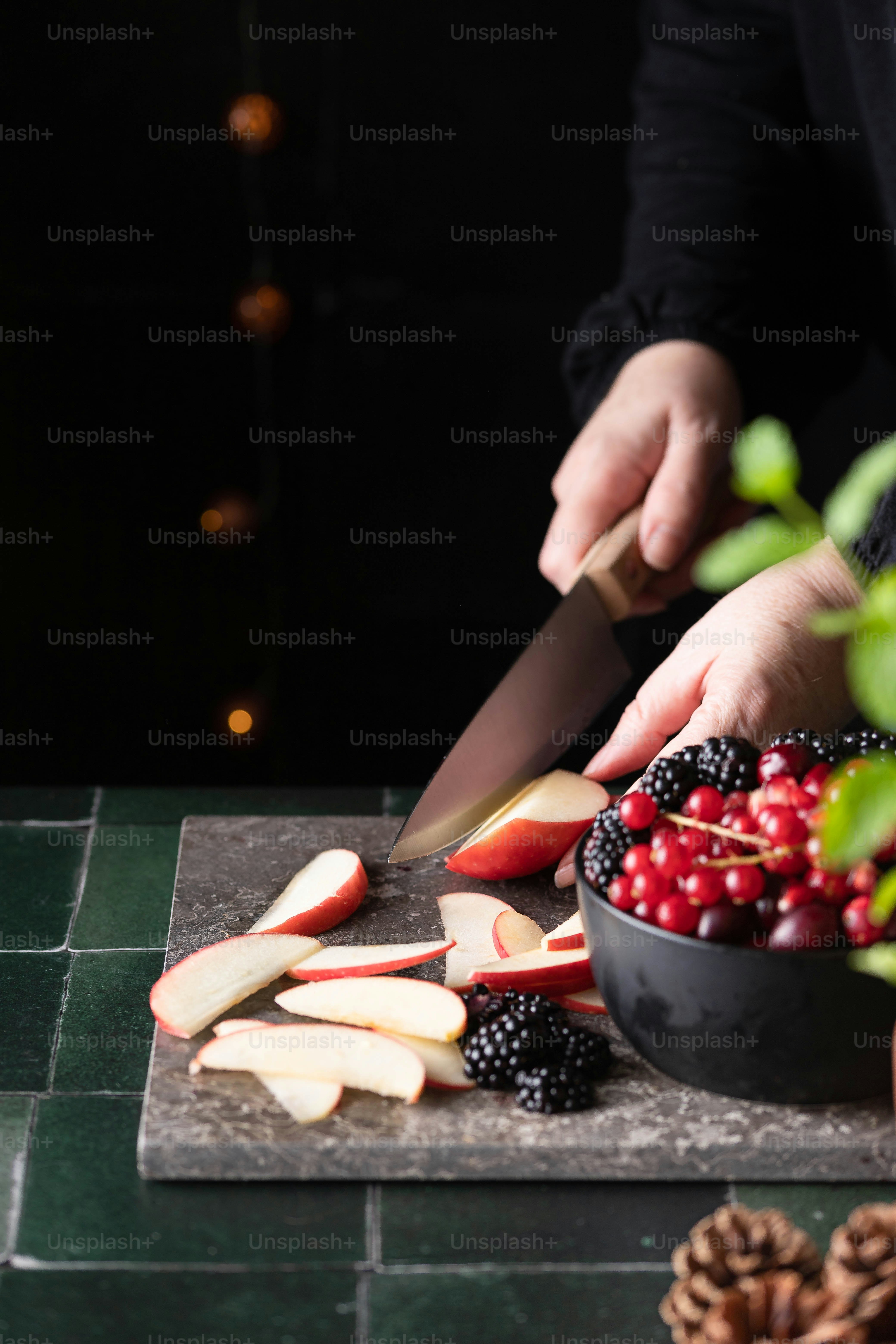 Foto Una persona cortando manzanas y bayas en una tabla de cortar ...