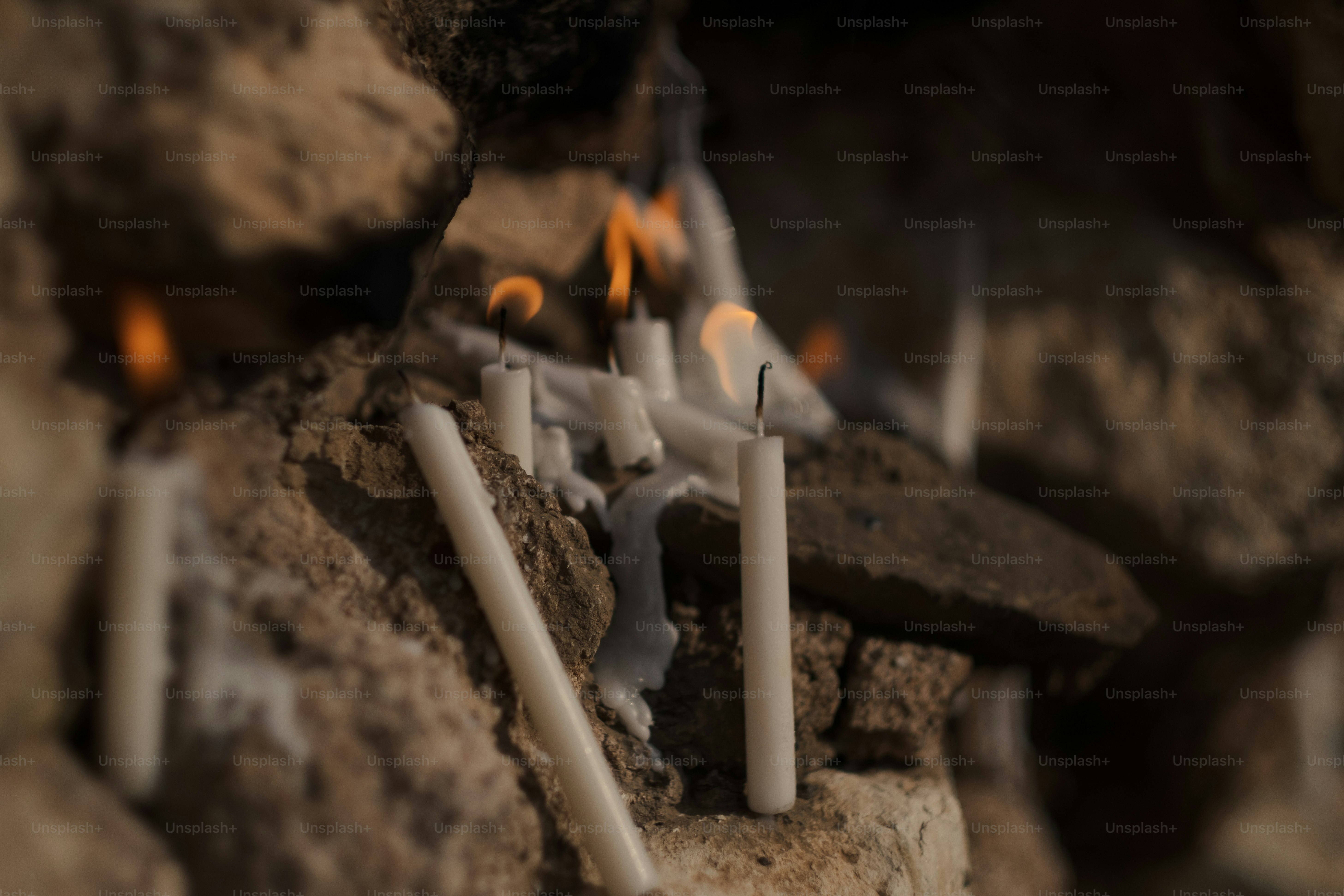 A bunch of candles that are on some rocks photo – Candle flame Image on ...