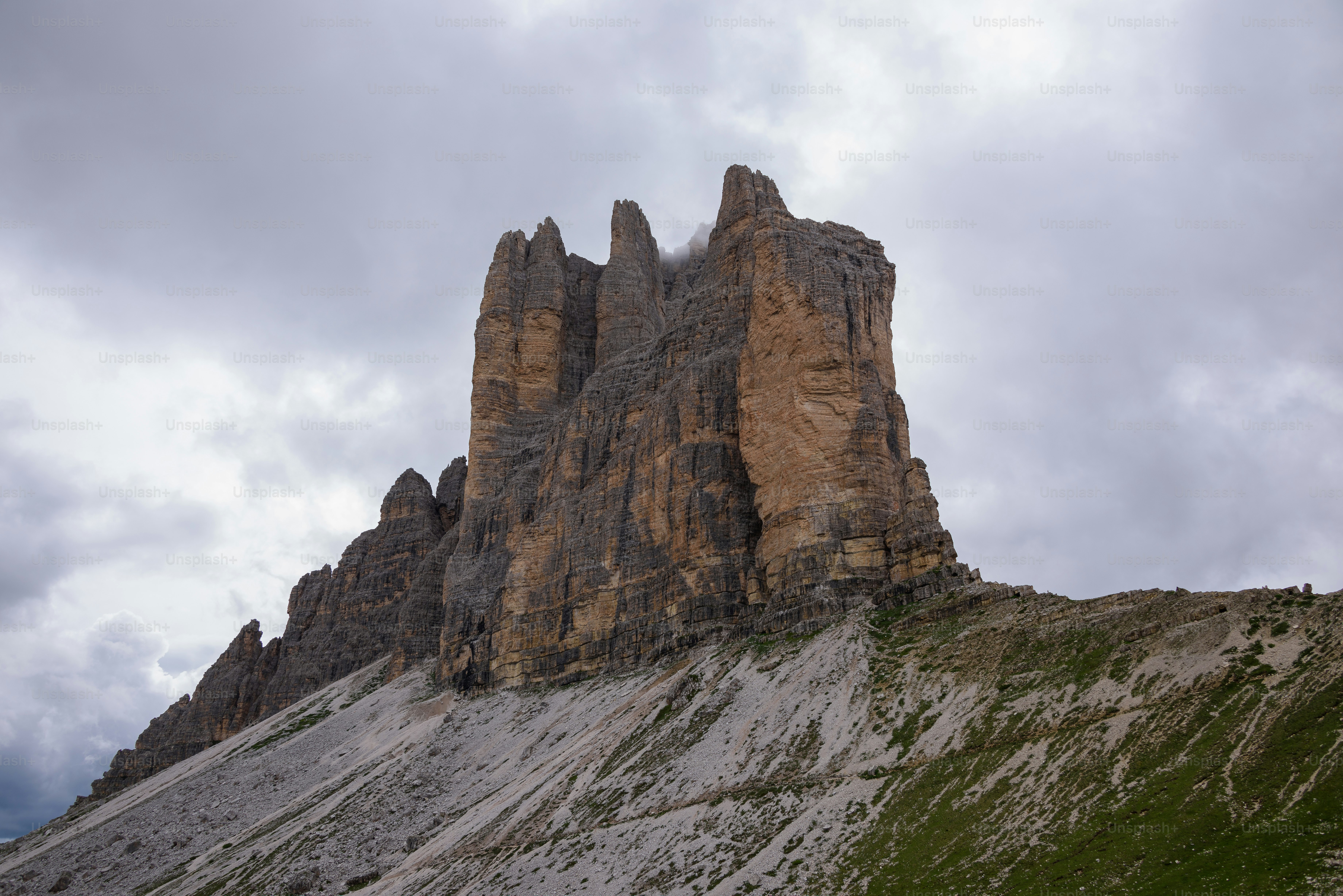 A very tall rock formation on a cloudy day photo – Mountains Image on ...
