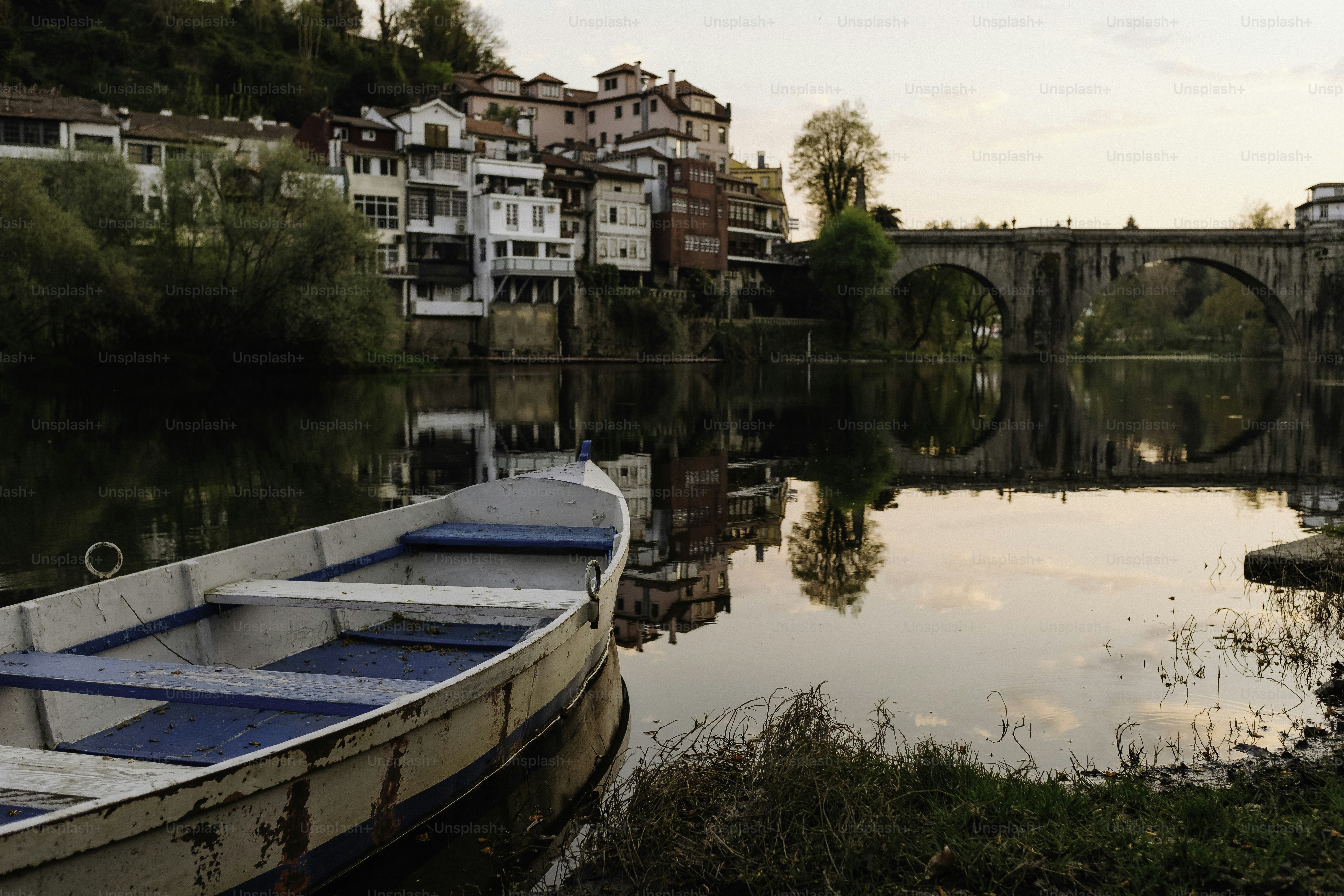 Foto Un pequeño bote sentado en la orilla de un río – Puente Imagen en ...
