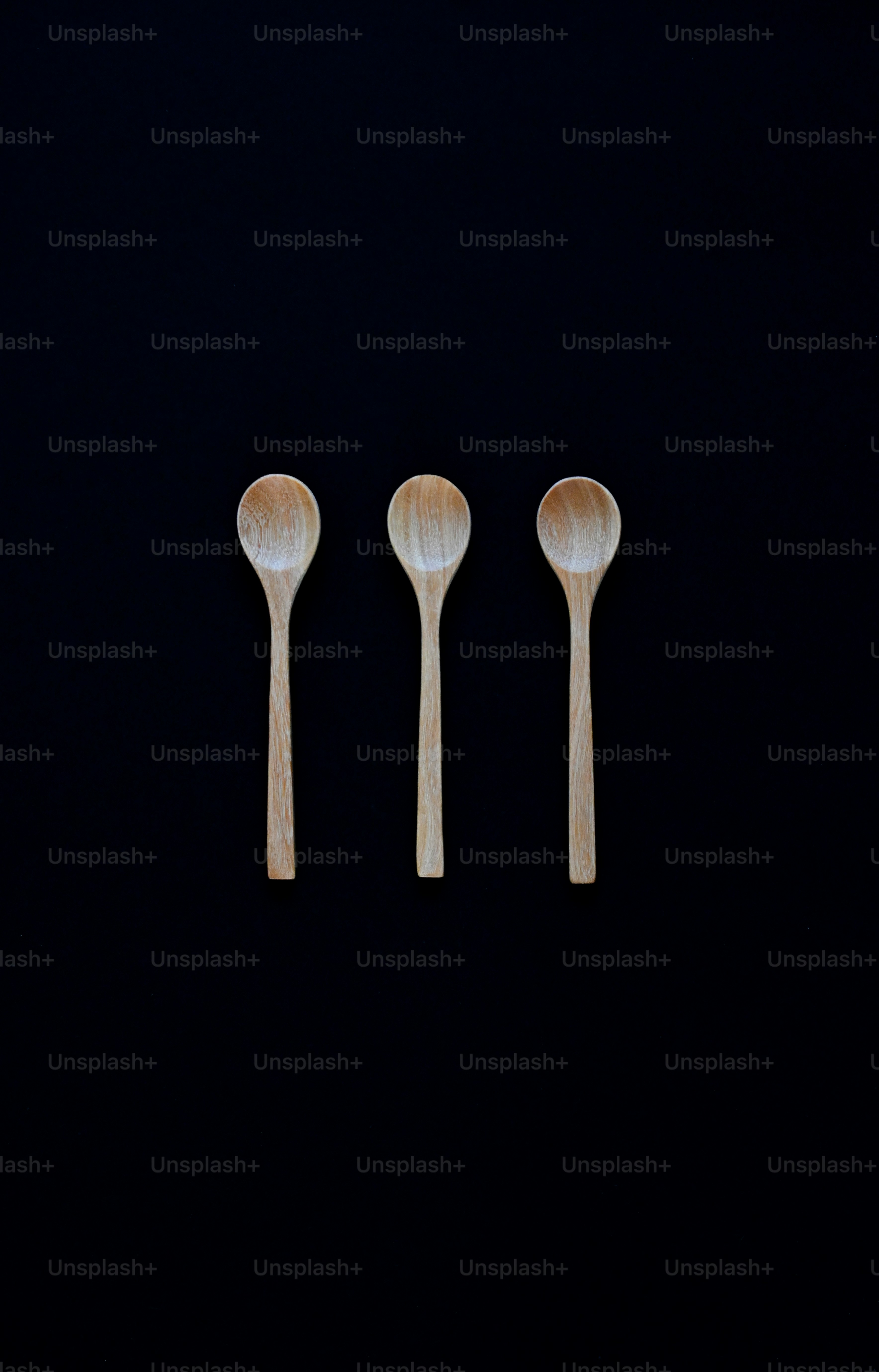 Three spoons are lined up on a yellow and black background photo ...