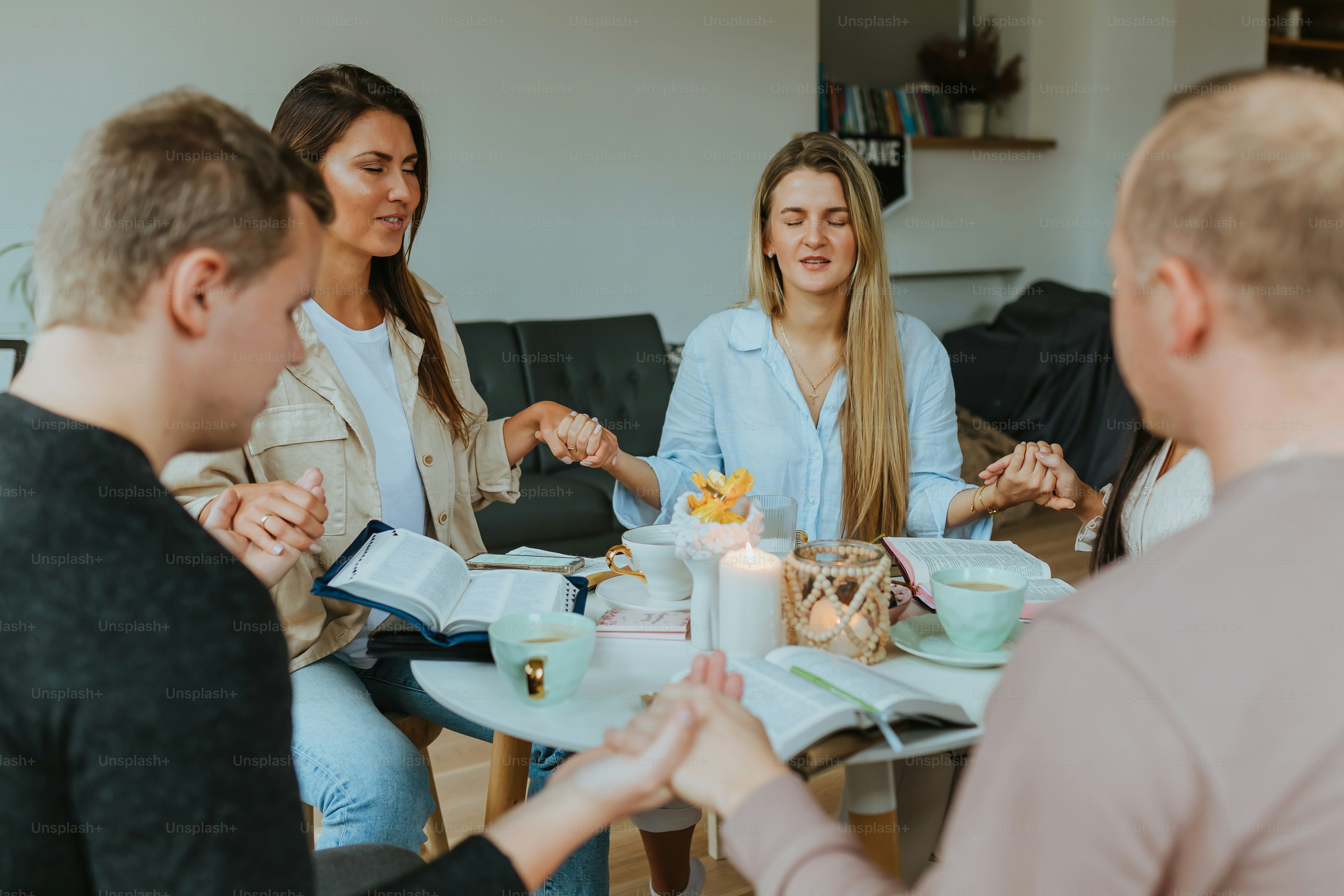 A group of people sitting around a table photo – Praying together Image ...