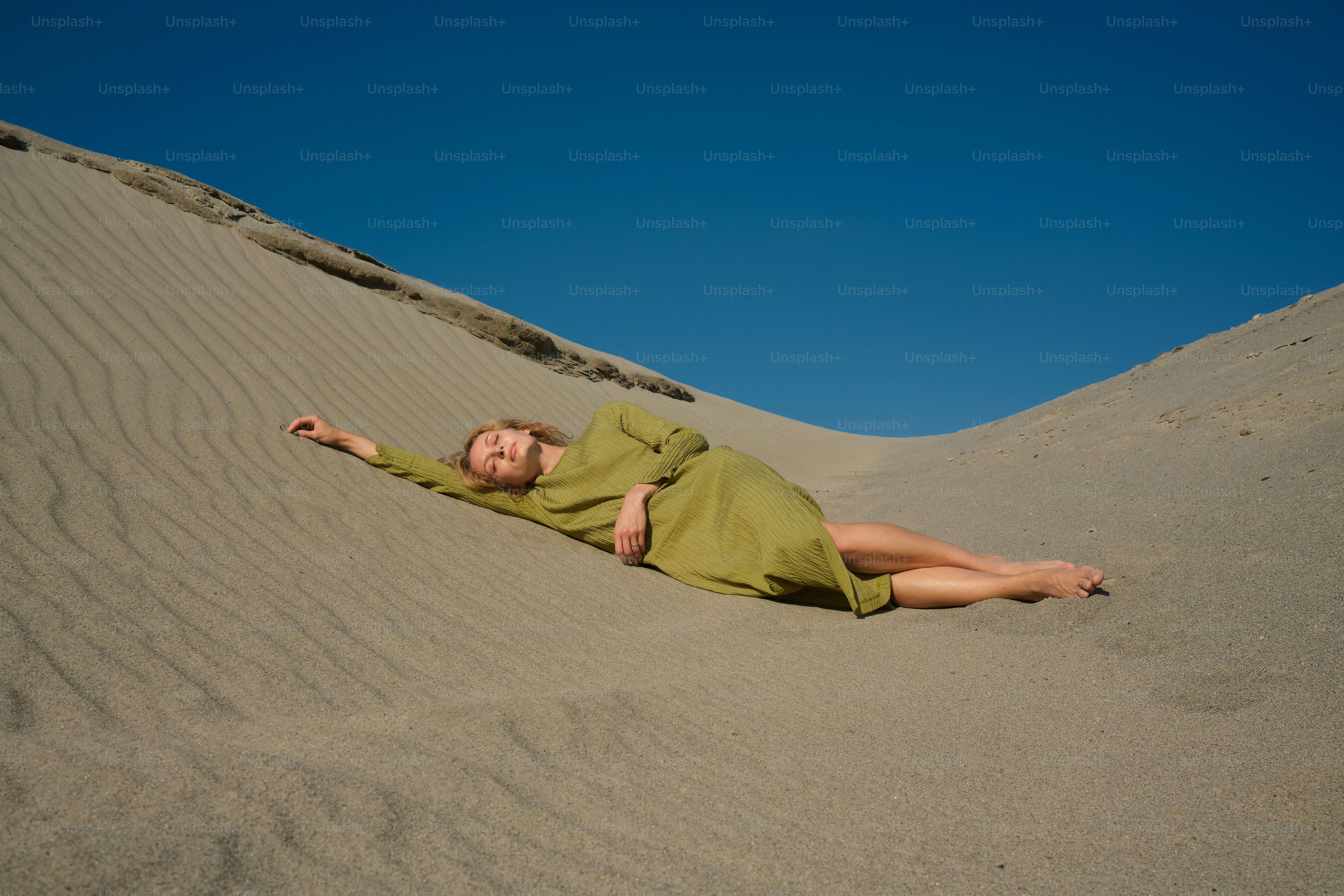 A woman in a green dress laying in the sand photo – Fashion Image on ...