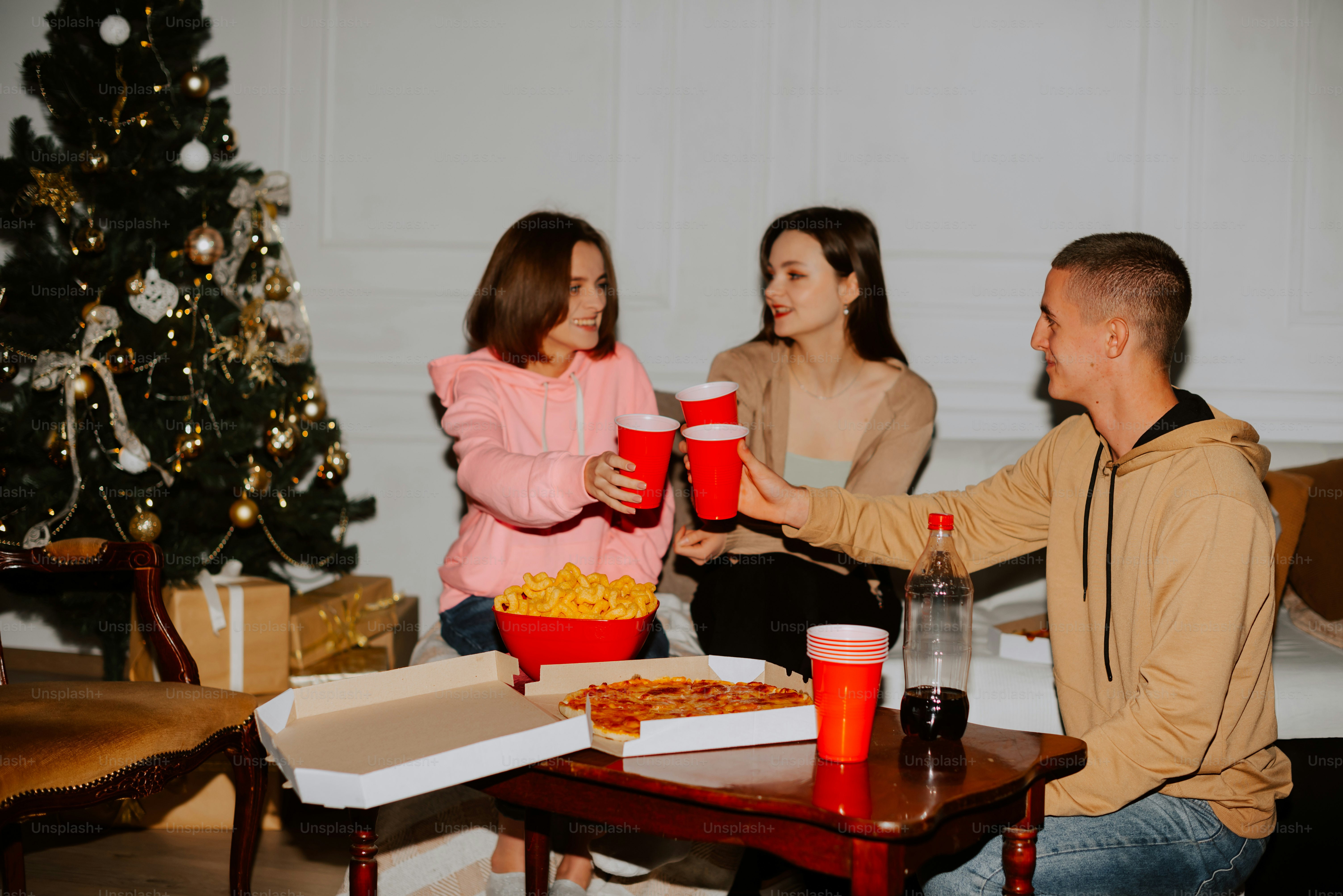 A group of people sitting around a christmas tree photo – Celebrations ...