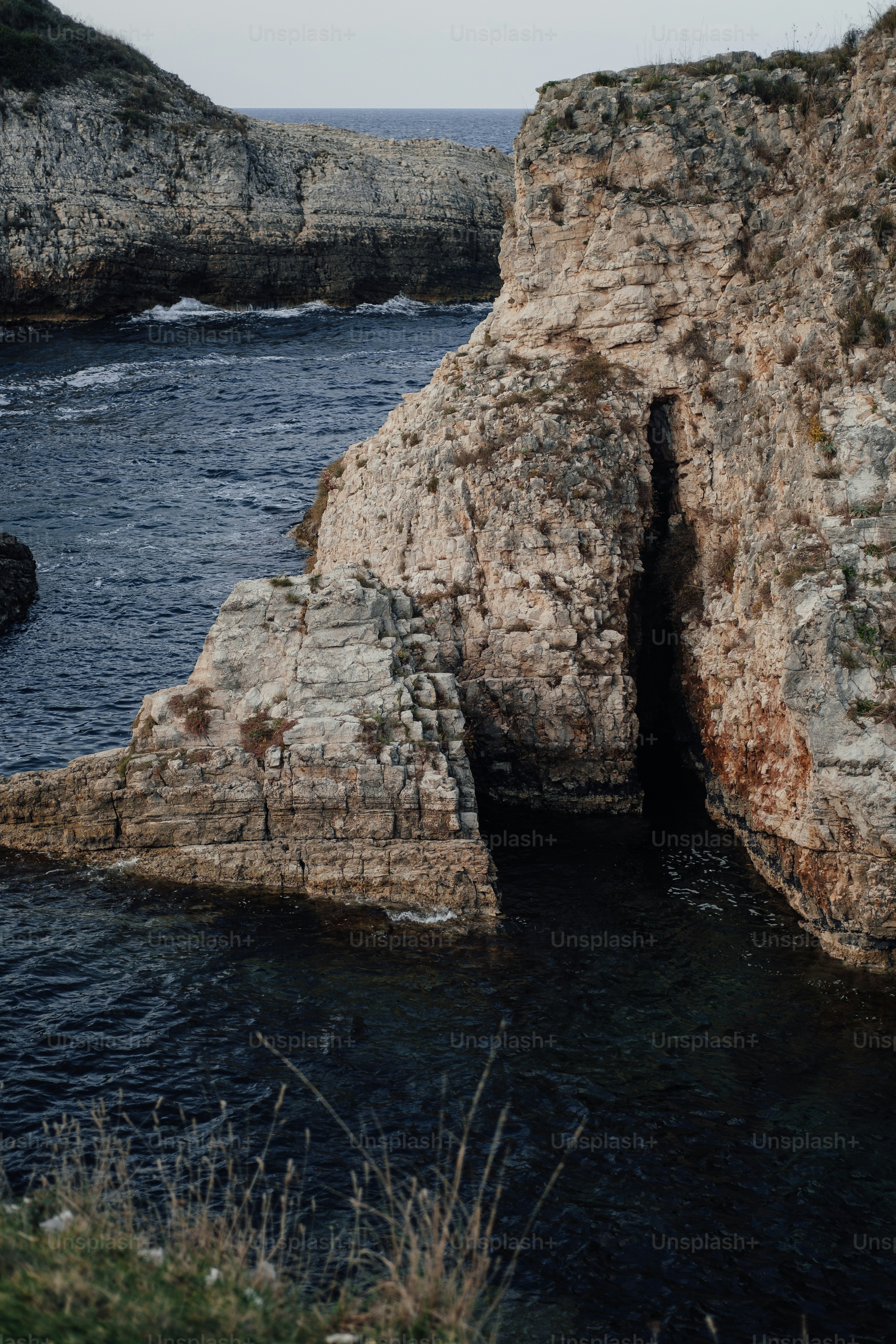 A large rock outcropping in the middle of a body of water photo – Coast ...