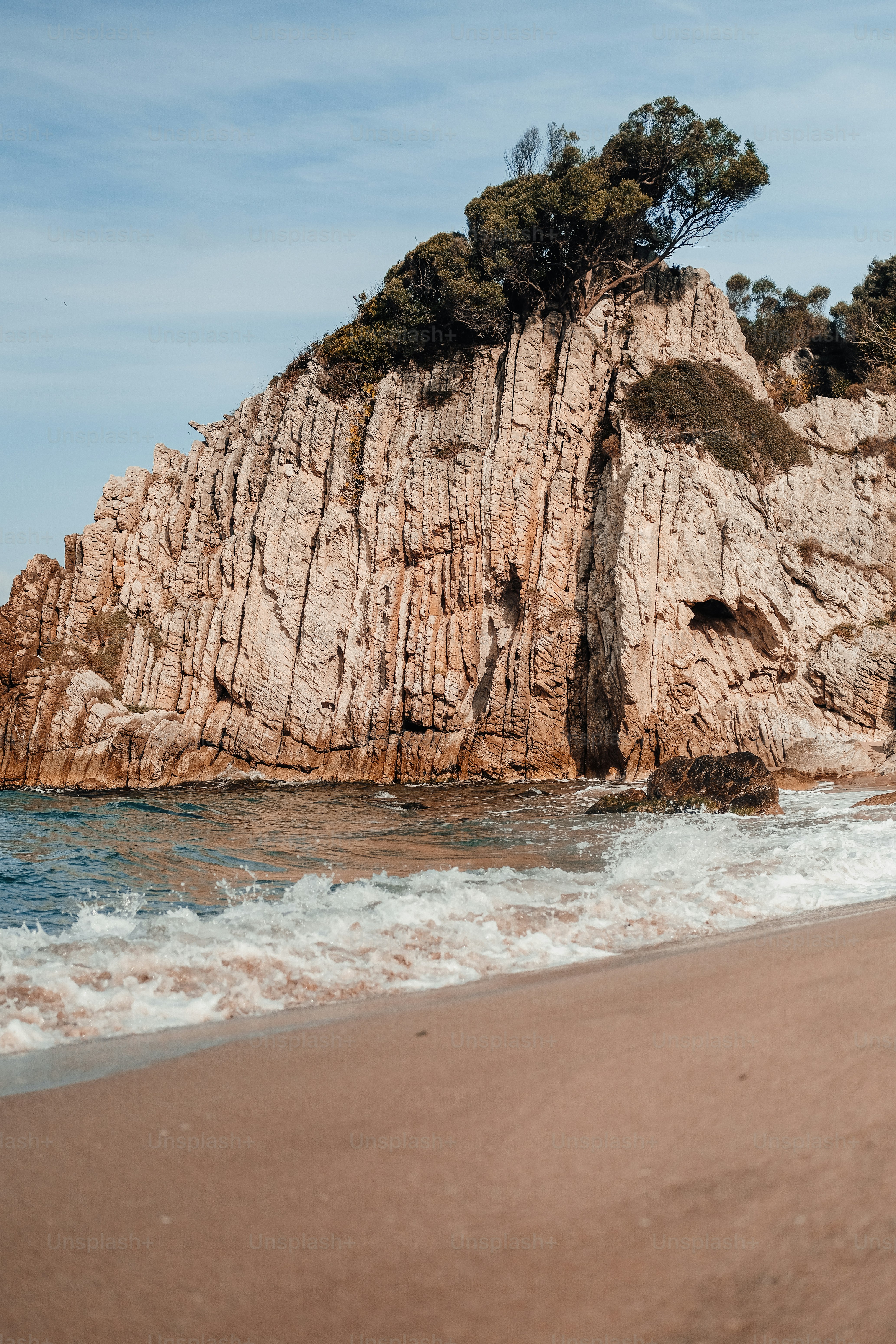 A large rock outcropping on a beach next to the ocean photo – Cliff ...
