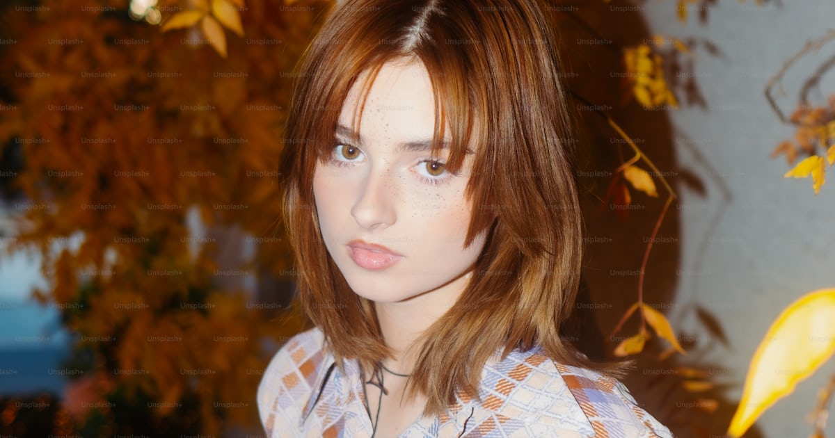 Una Mujer Joven Parada Frente A Un árbol Foto Imagen De Moda En Unsplash