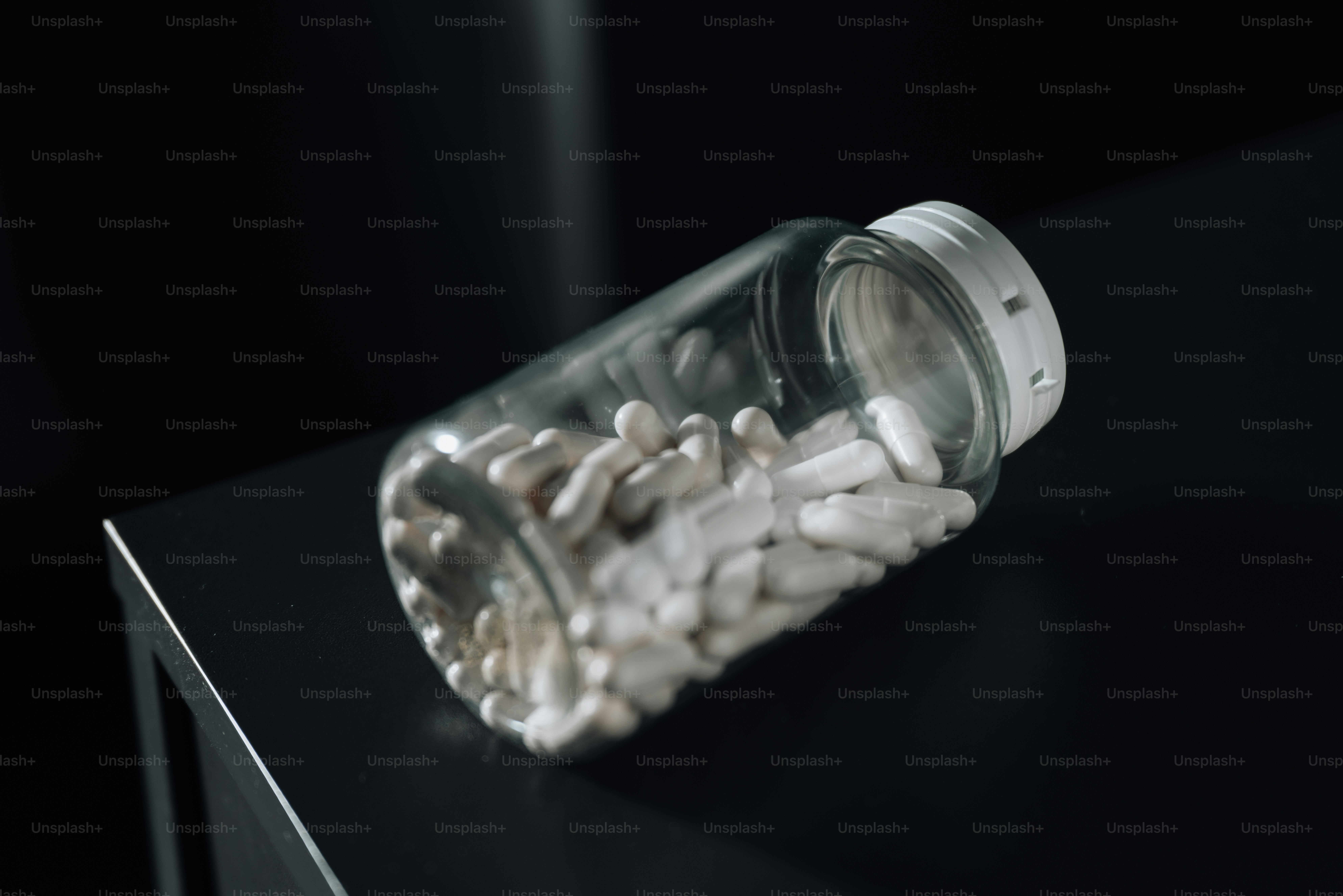 A glass jar filled with white pills sitting on top of a table photo ...