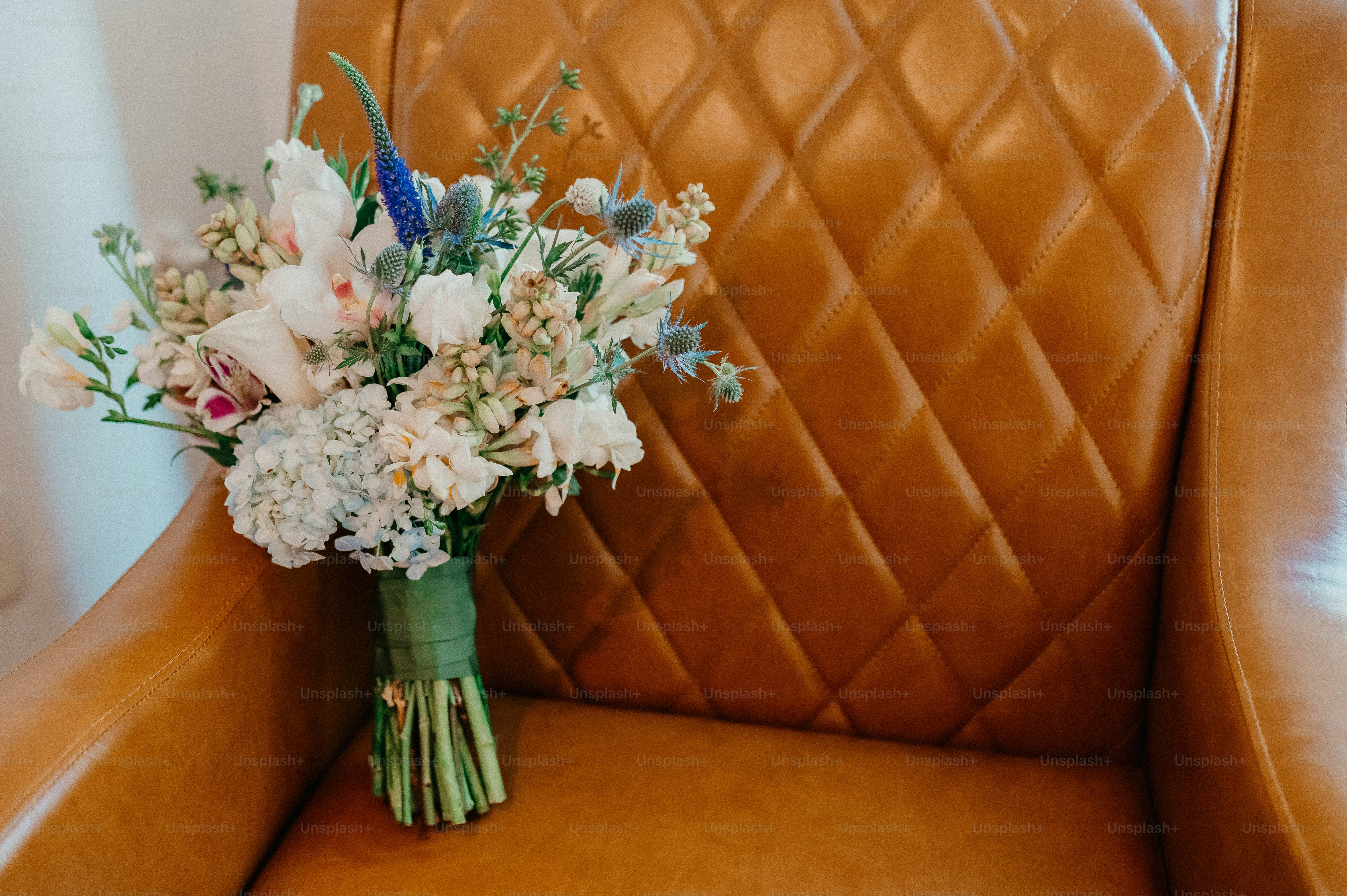 A bouquet of flowers sitting on a leather chair photo – Armchair Image ...