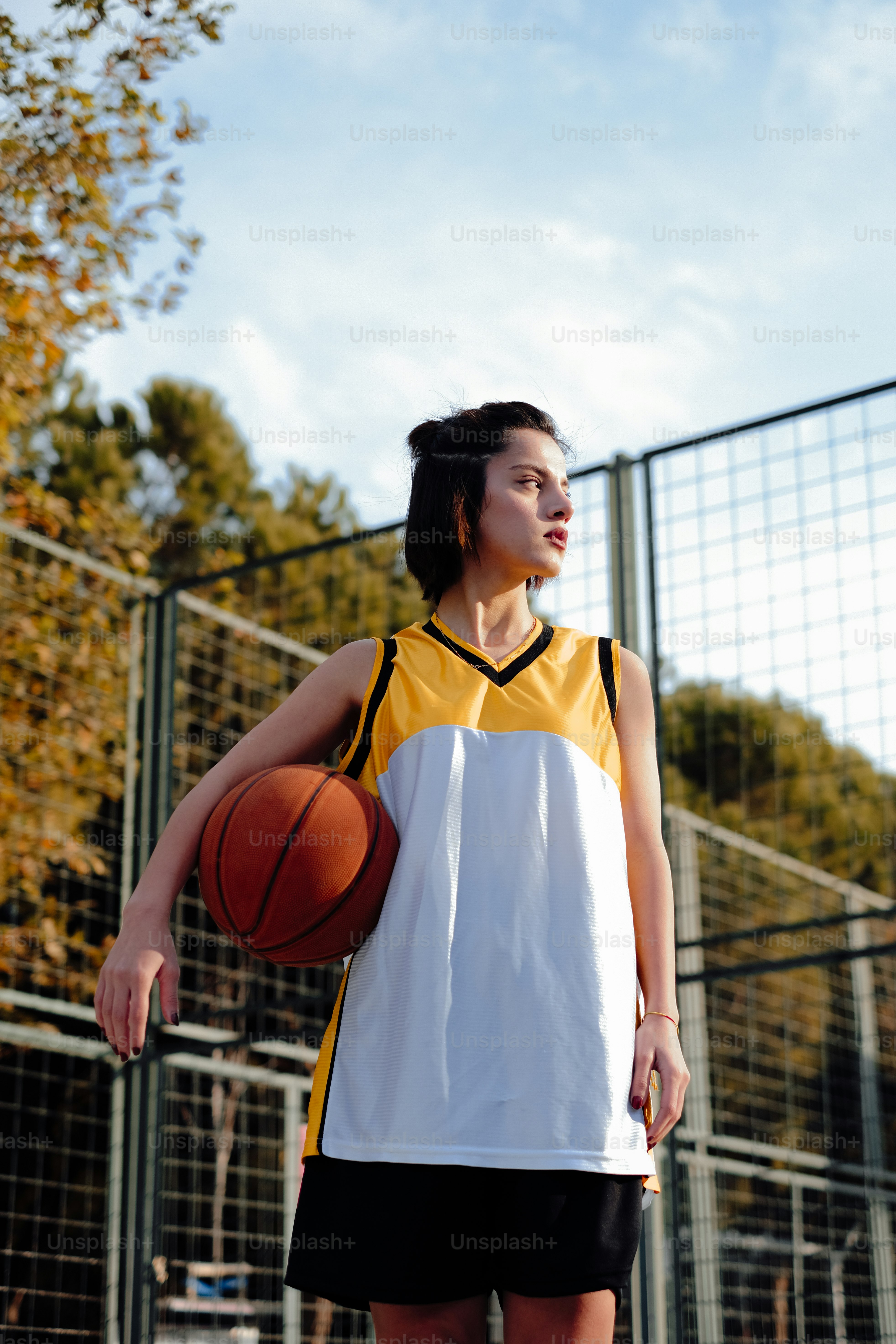 A woman in a yellow and white dress holding a basketball photo ...