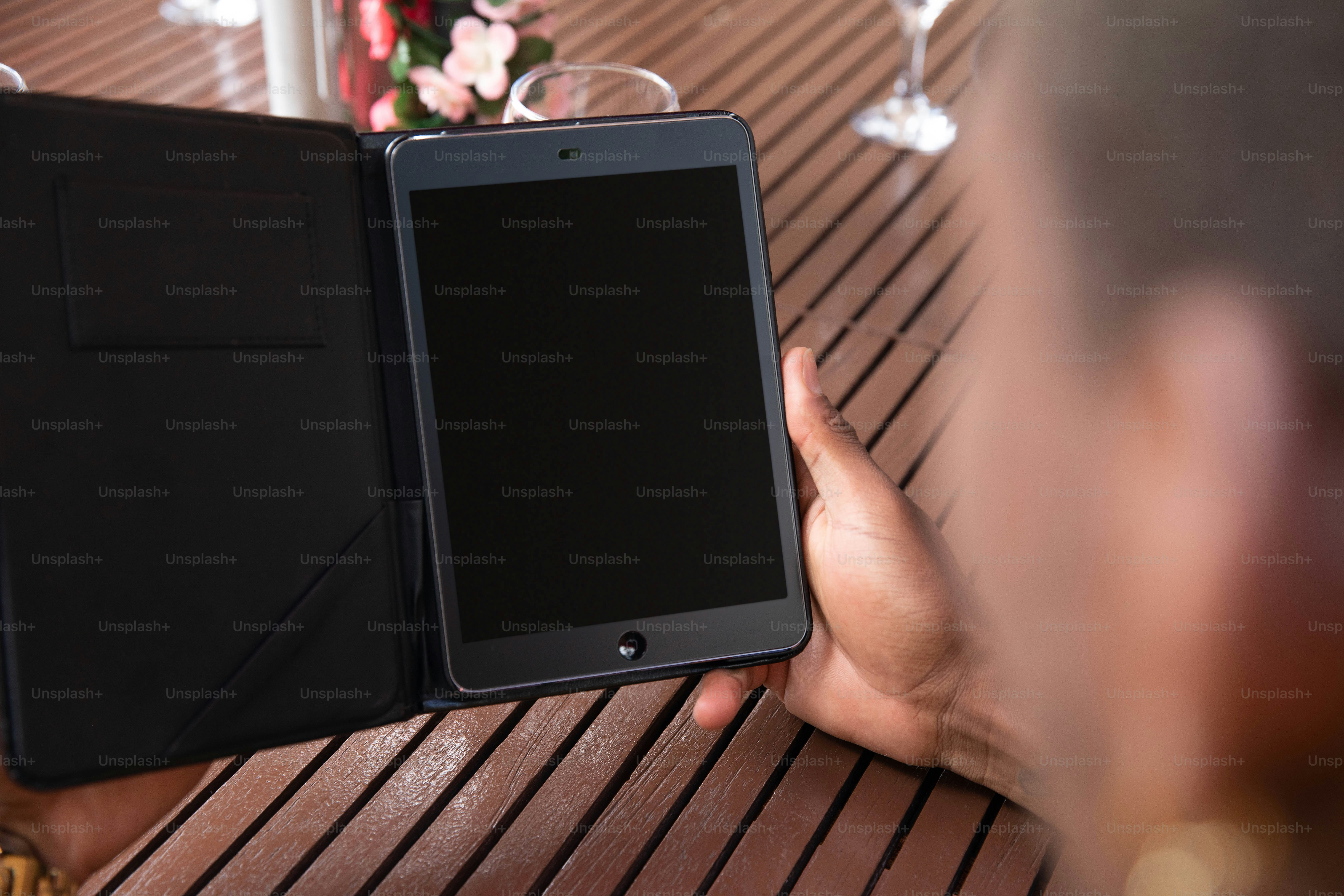 A man holding a tablet computer on top of a wooden table photo ...