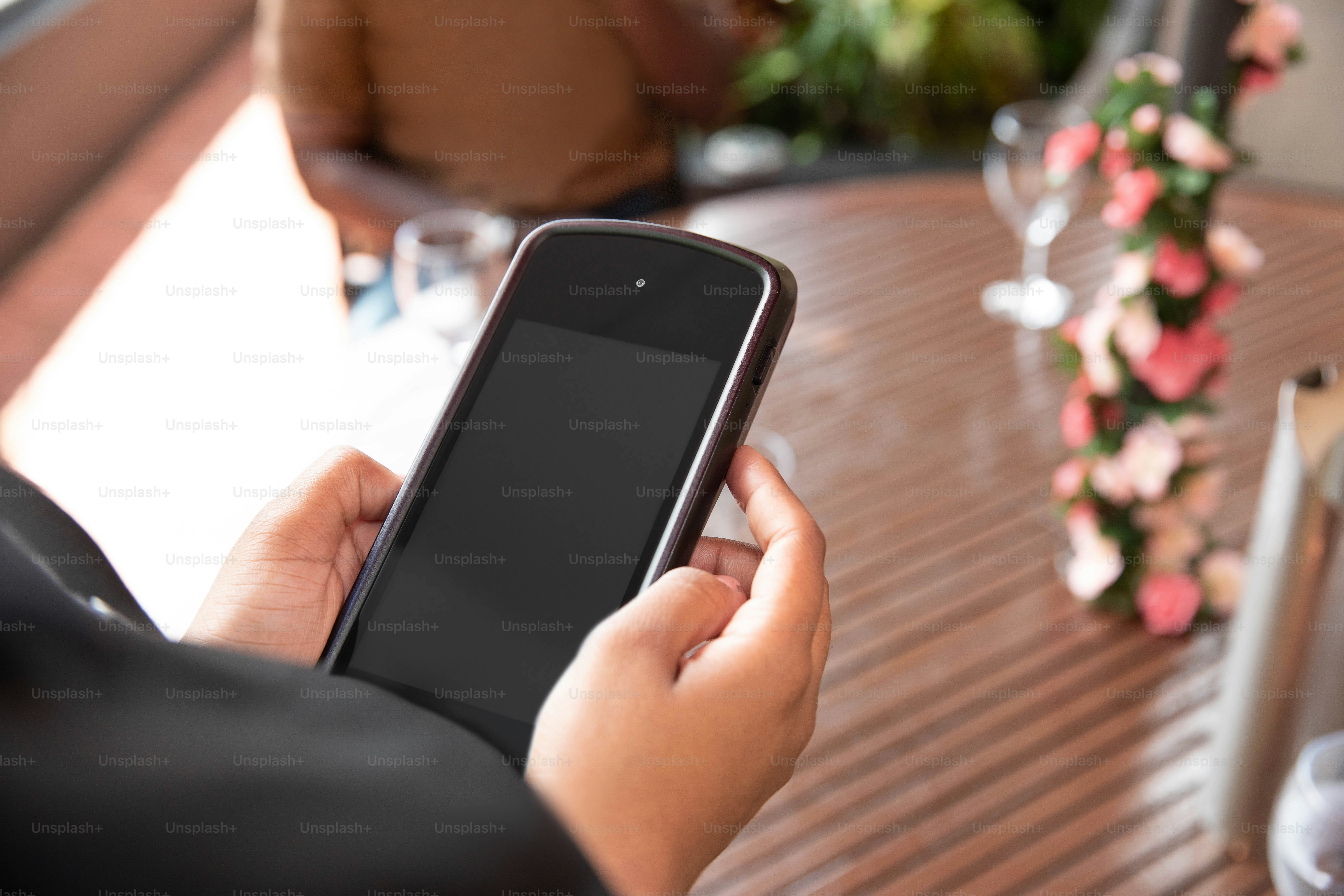 A person sitting at a table using a cell phone photo – Using Image on ...