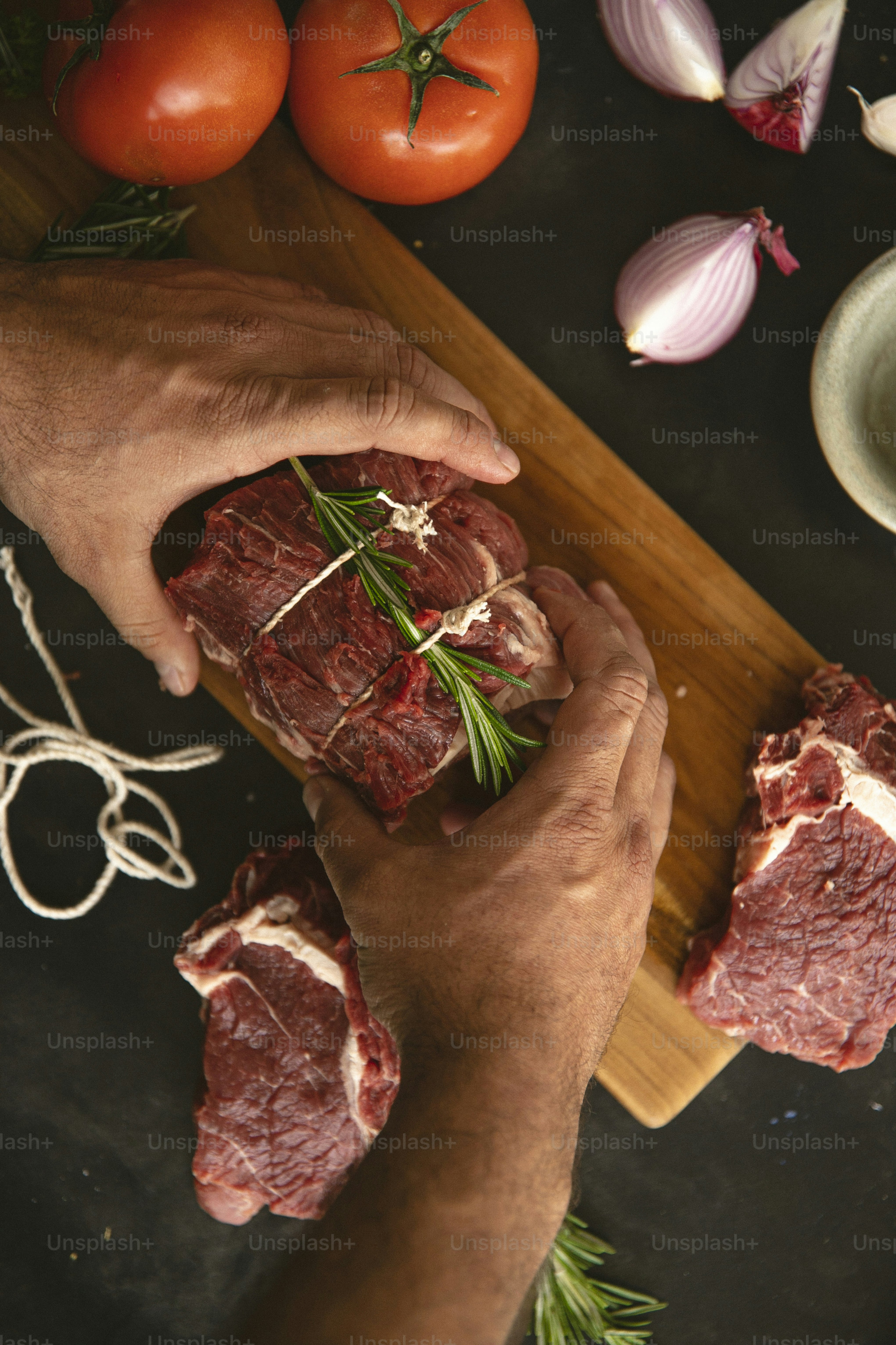 A person holding a piece of meat on a cutting board photo – Food and ...