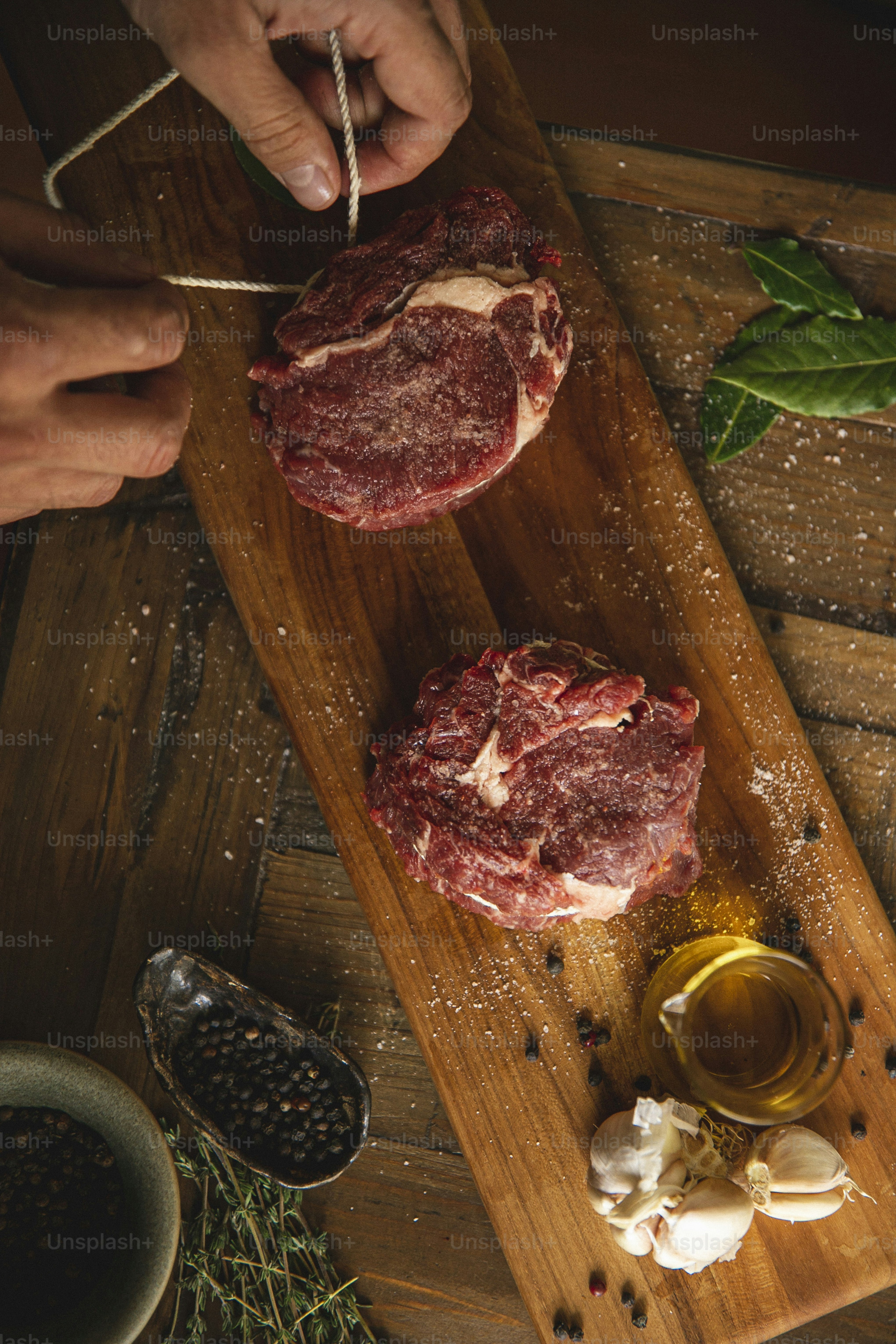 A person sprinkling seasoning on some meat on a cutting board photo ...