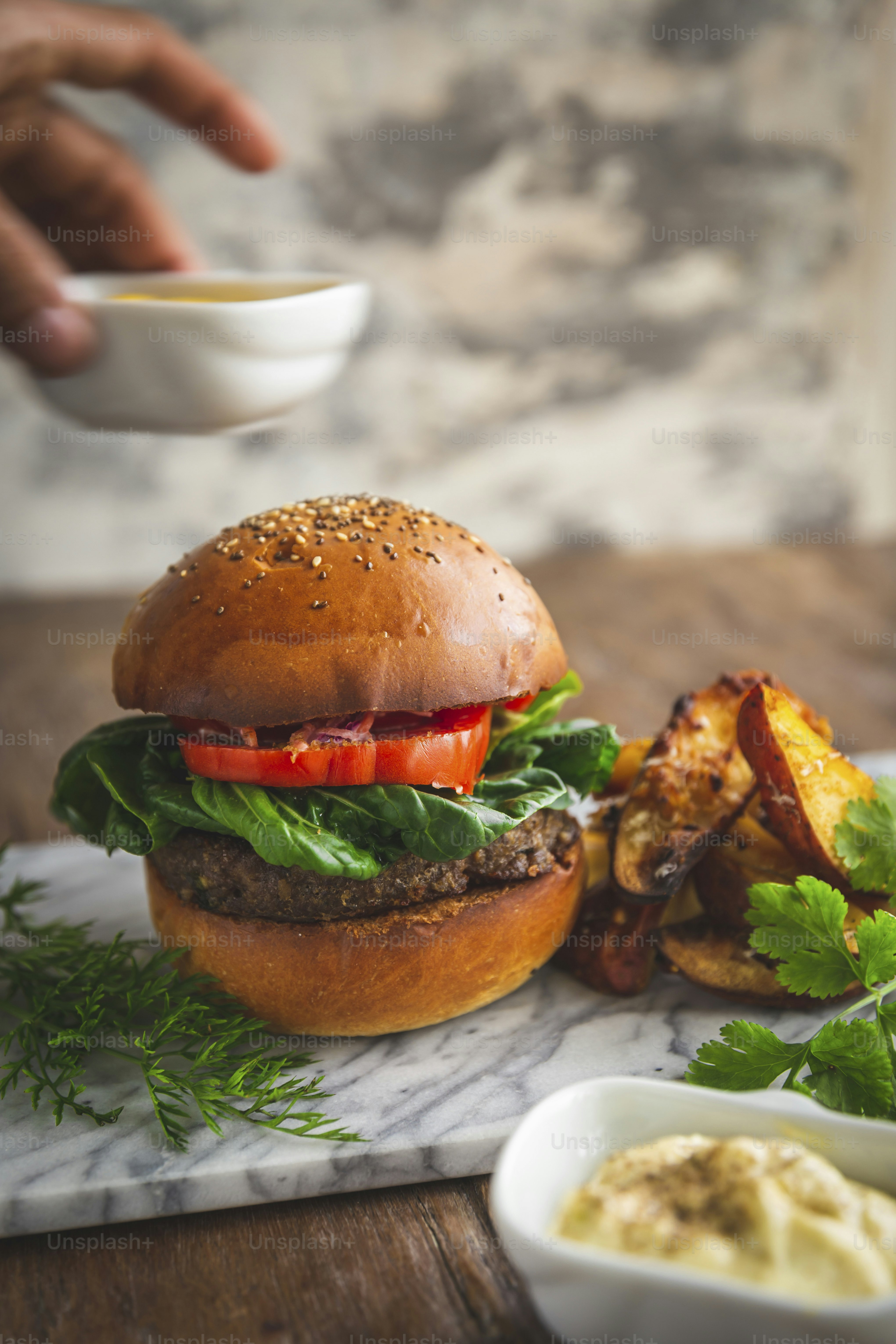 A hamburger with lettuce, tomato, and a side of potato wedges photo ...