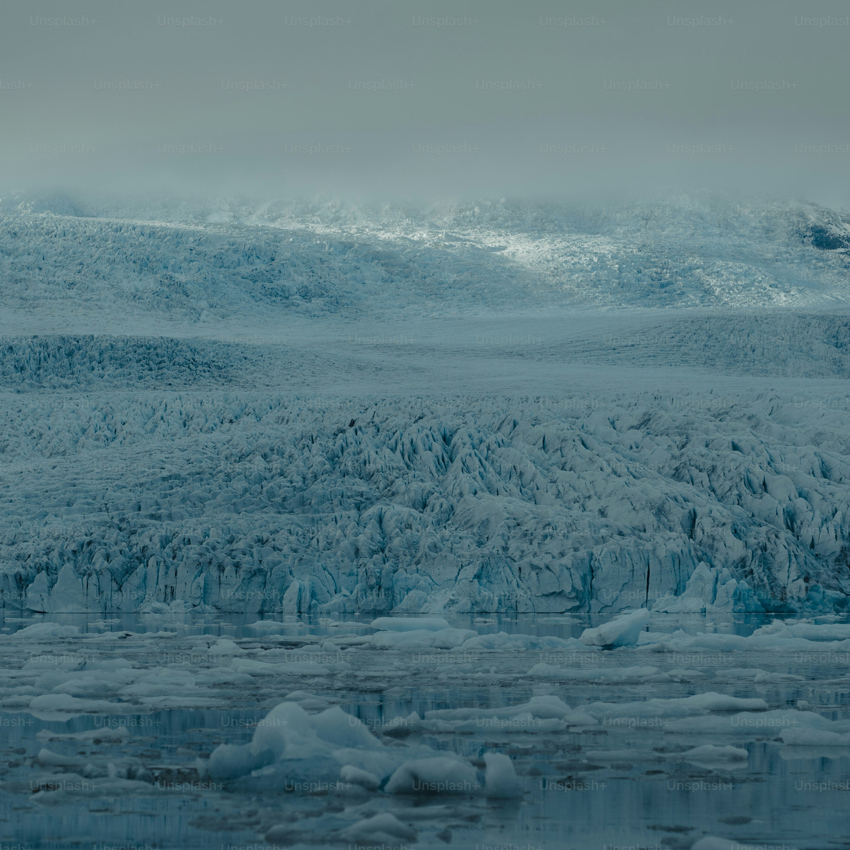 A mountain covered in lots of ice next to a body of water photo ...