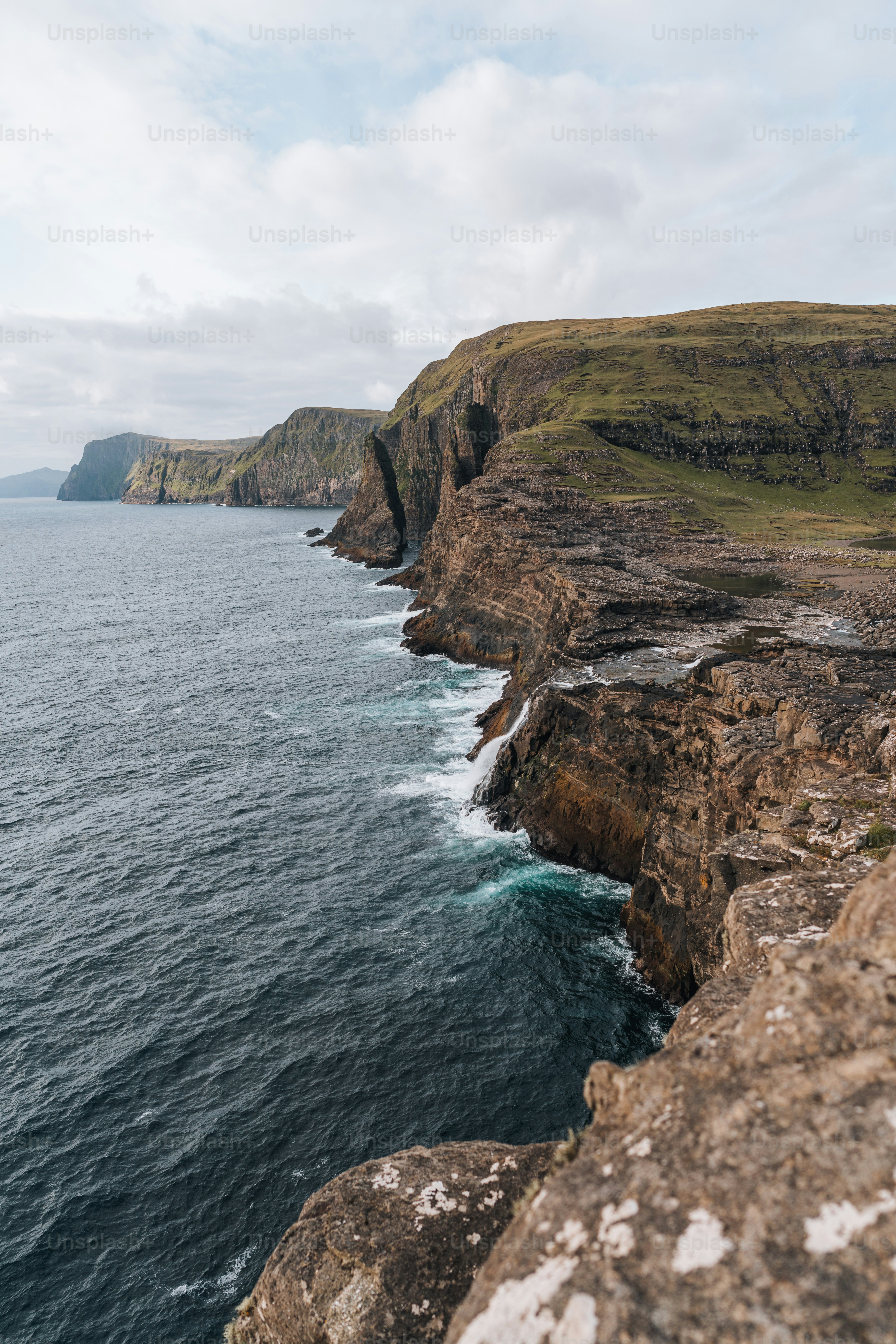 A rocky cliff overlooks a body of water photo – Nature beauty Image on ...