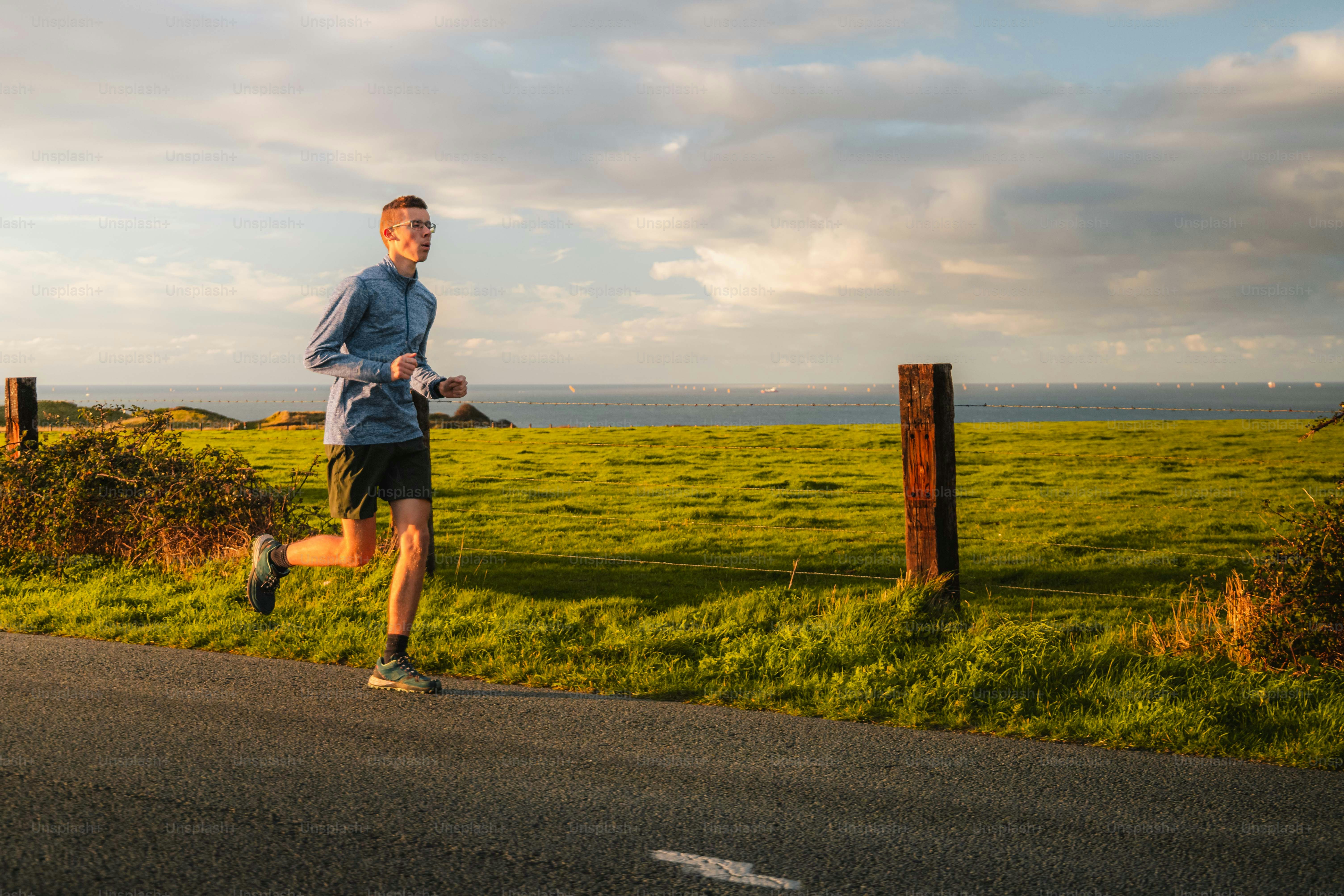 A man running down a road near a field photo – Runners Image on Unsplash