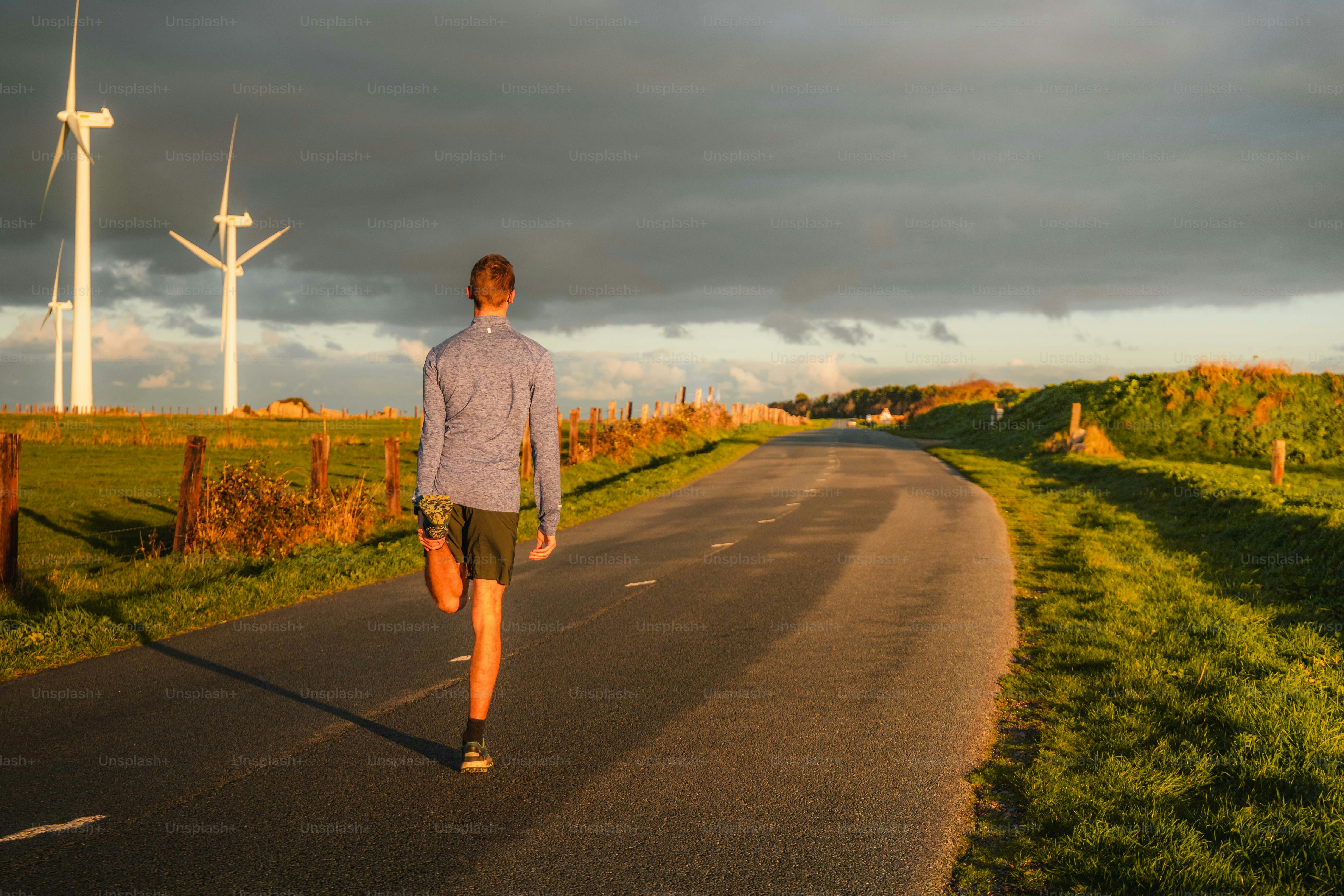 A man running down a road with a sky background photo – Runner Image on ...