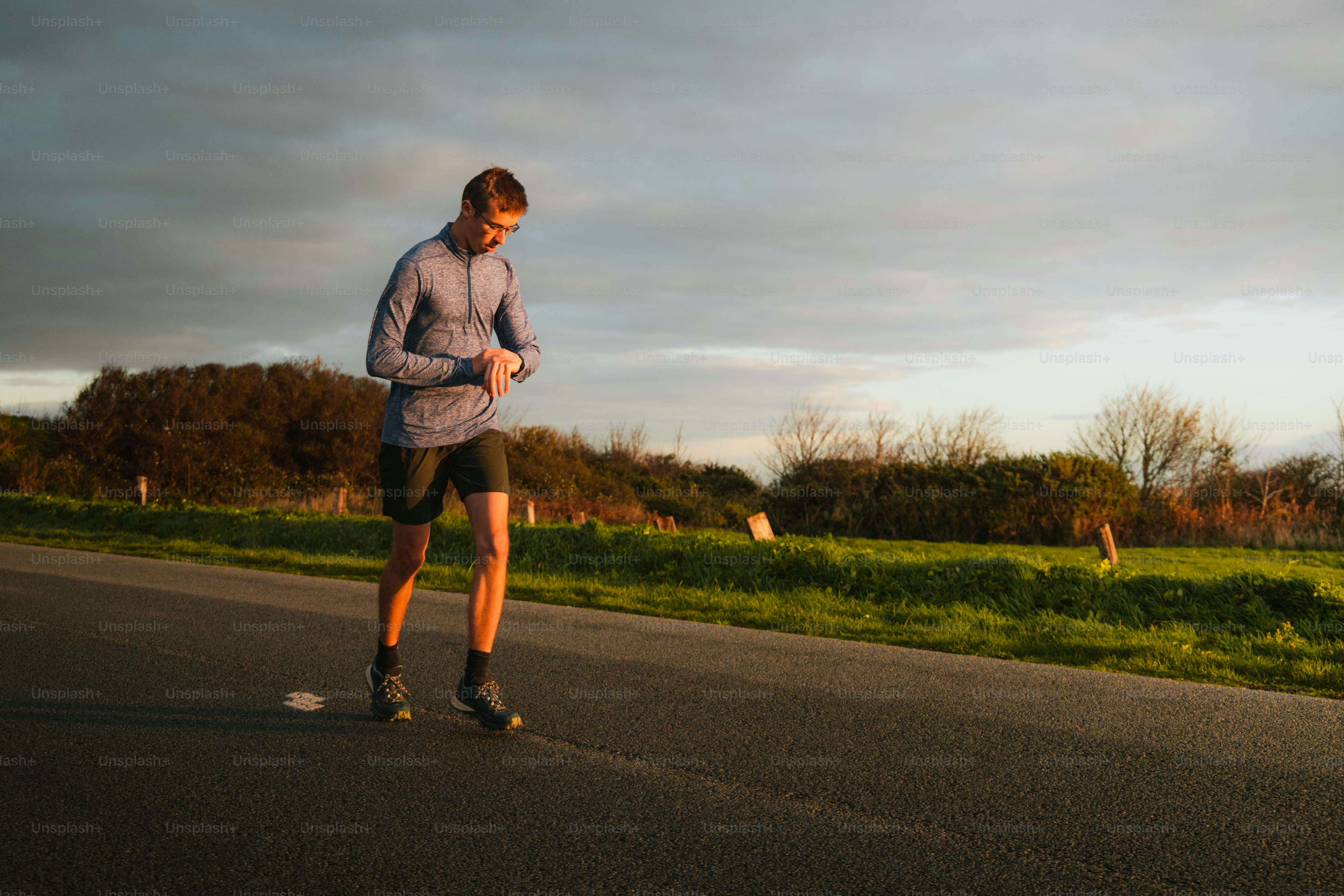 A man running down a road near a field photo – Runners Image on Unsplash