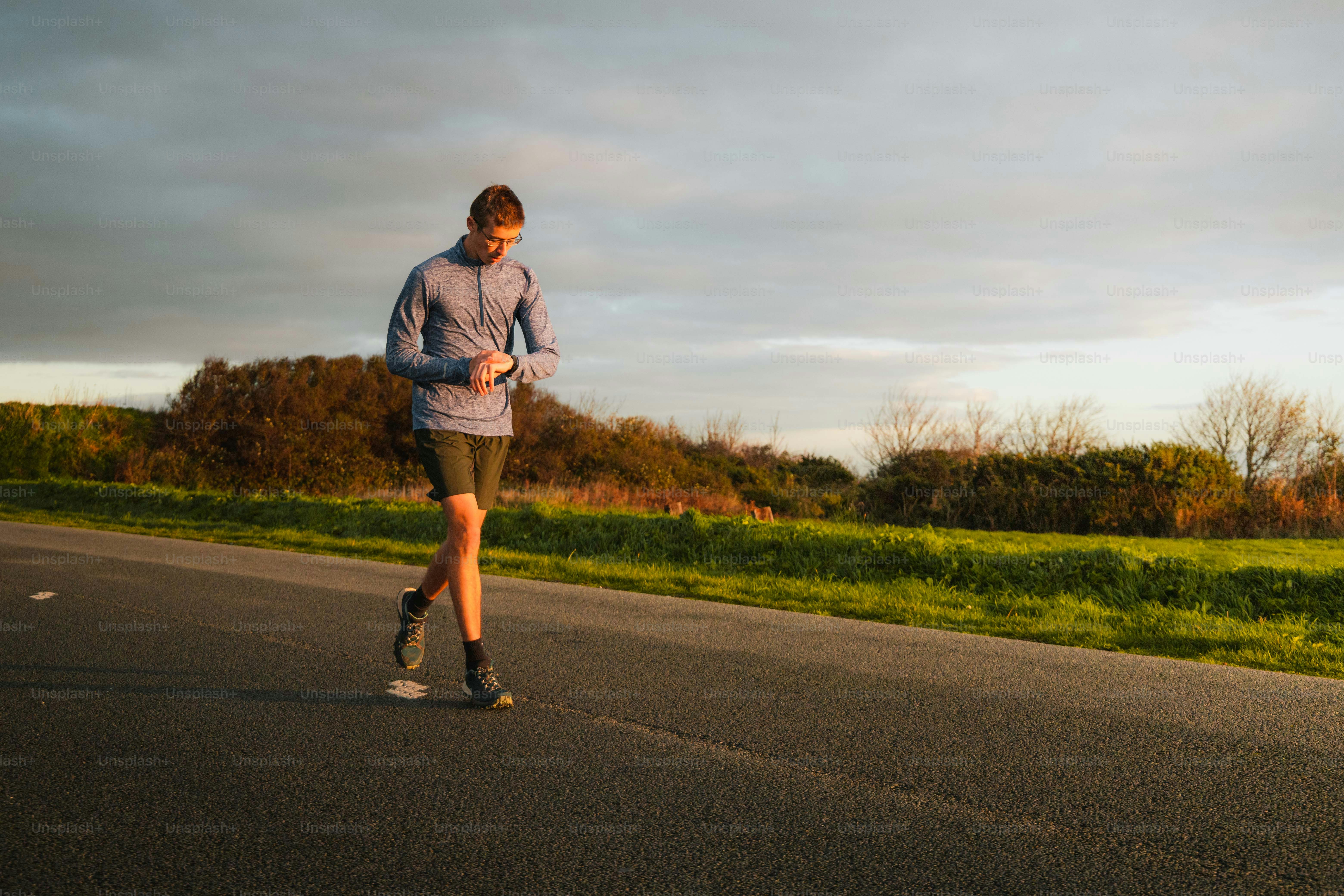 A man running down a road in the middle of the day photo – Runner Image ...