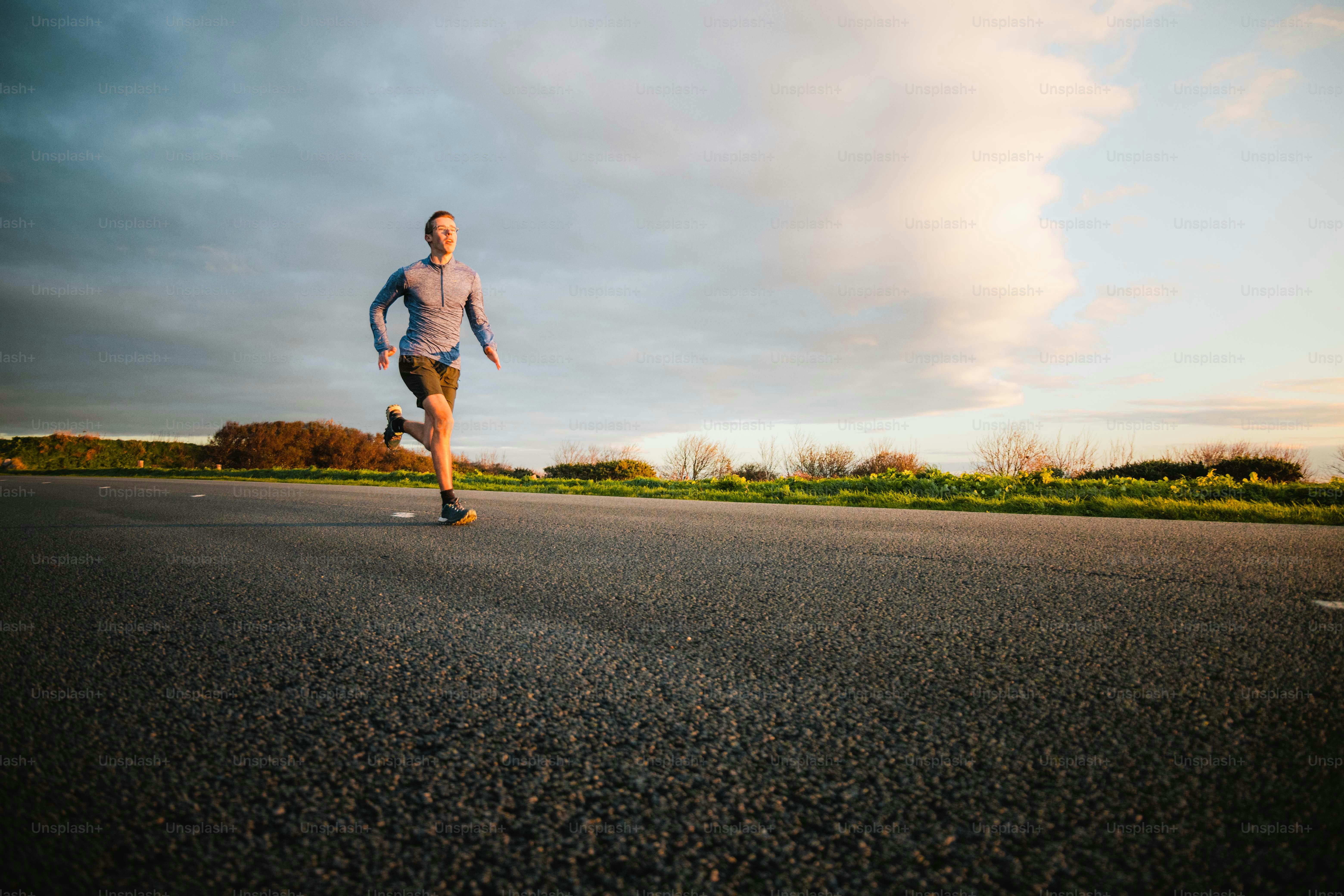 A man running down a road in the middle of the day photo – Sunset Image ...
