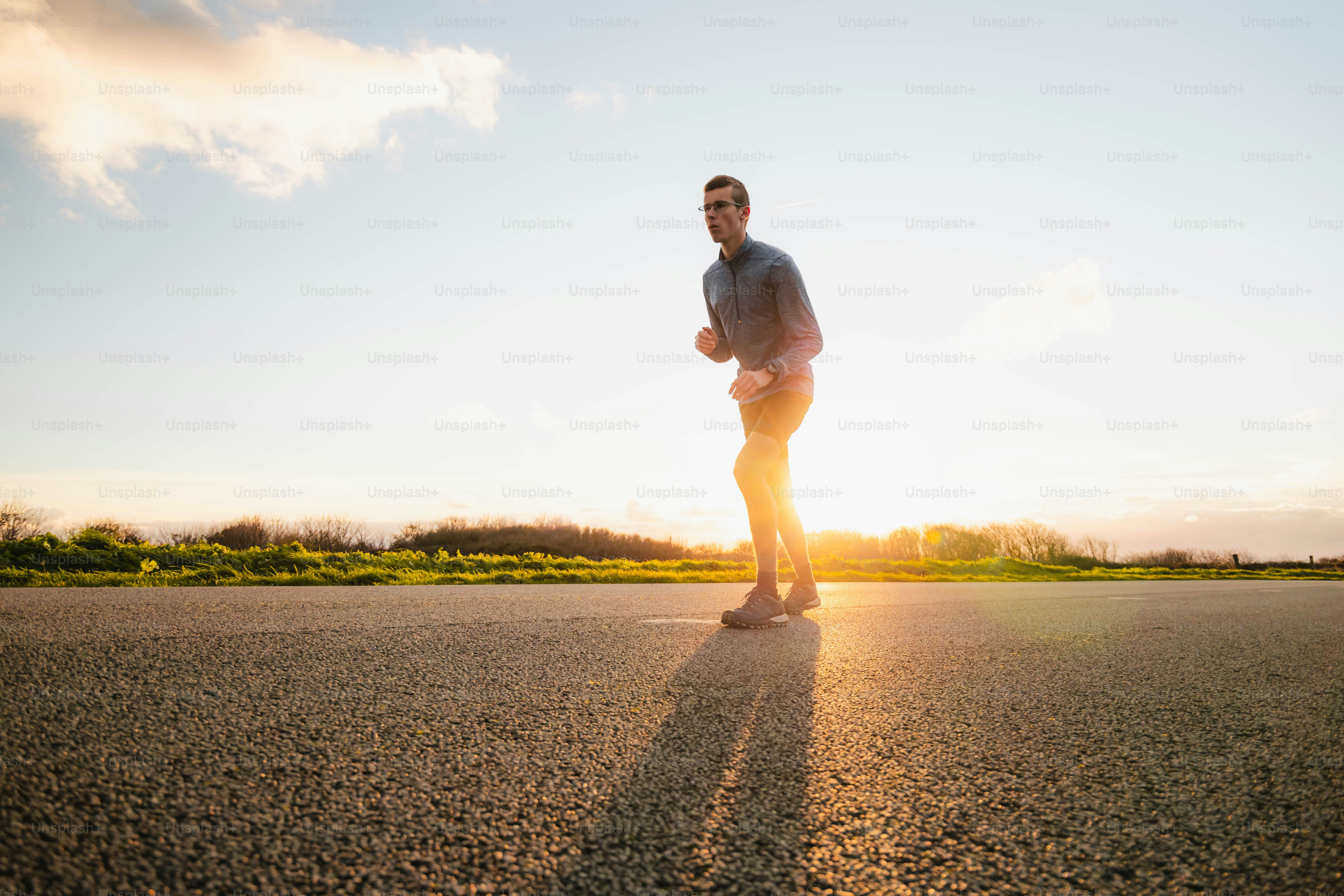 A man running down a road in the middle of the day photo – Runner Image ...